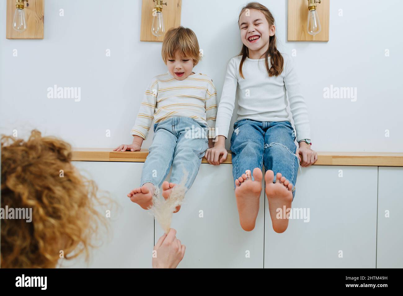 Mamma solletico i piedi dei suoi figli con un soffice ciuffo di cereali ...