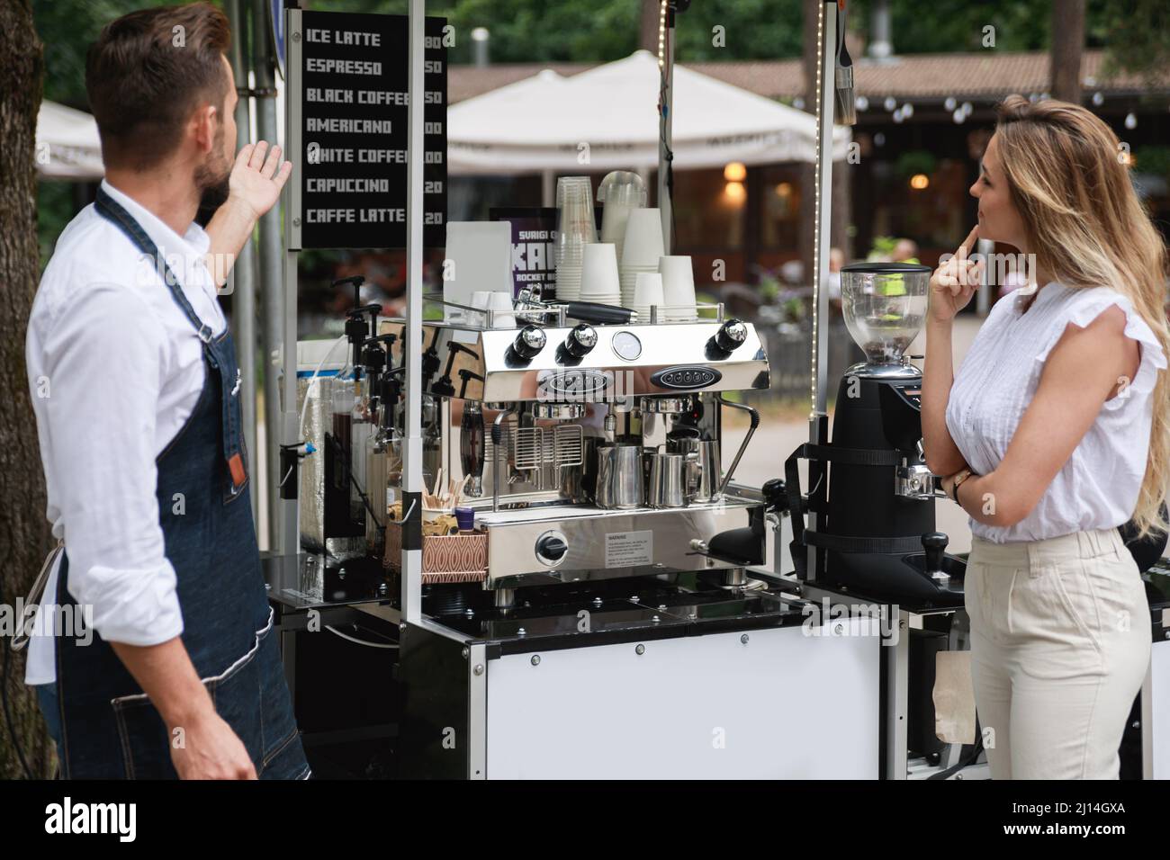 Barista uomo offrire di scegliere vari tipi di caffè per la donna ...