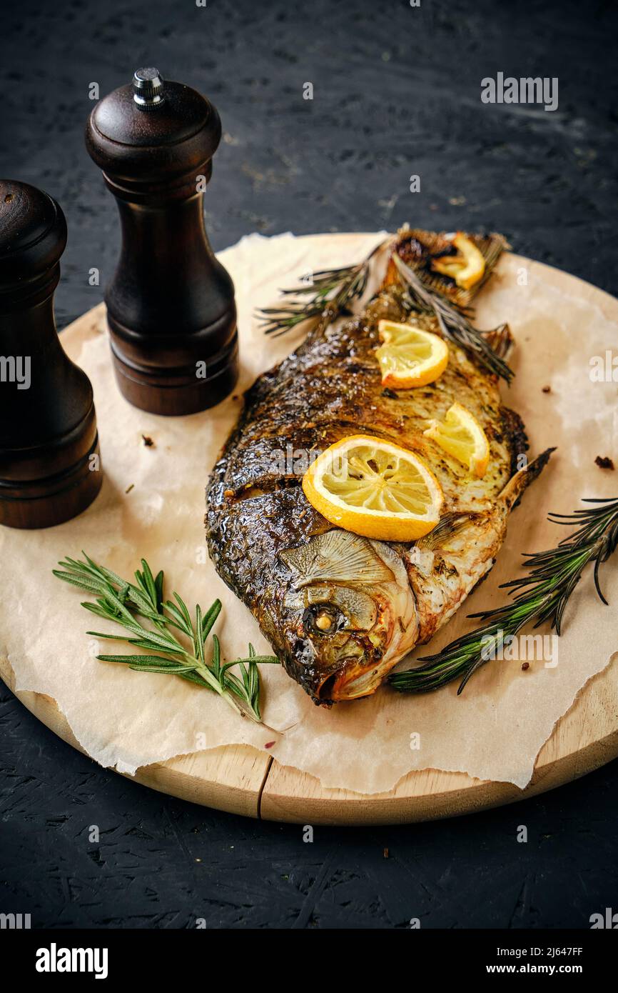 Pesce cotto al forno con limone e rosmarino posato tagliere e pergamena ...