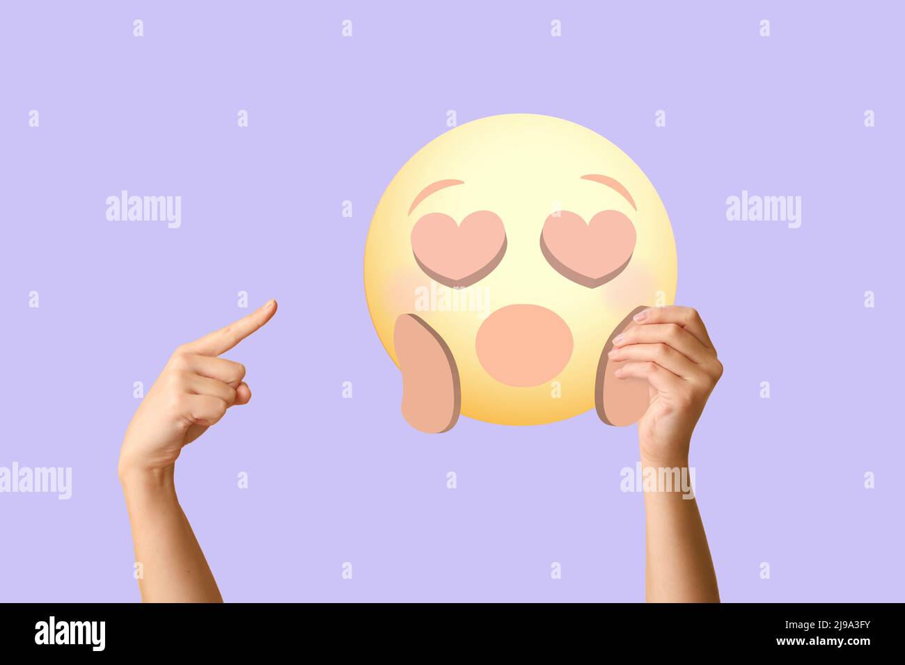 Le mani femminili tengono emoticon stupito con occhi a forma di cuore ...