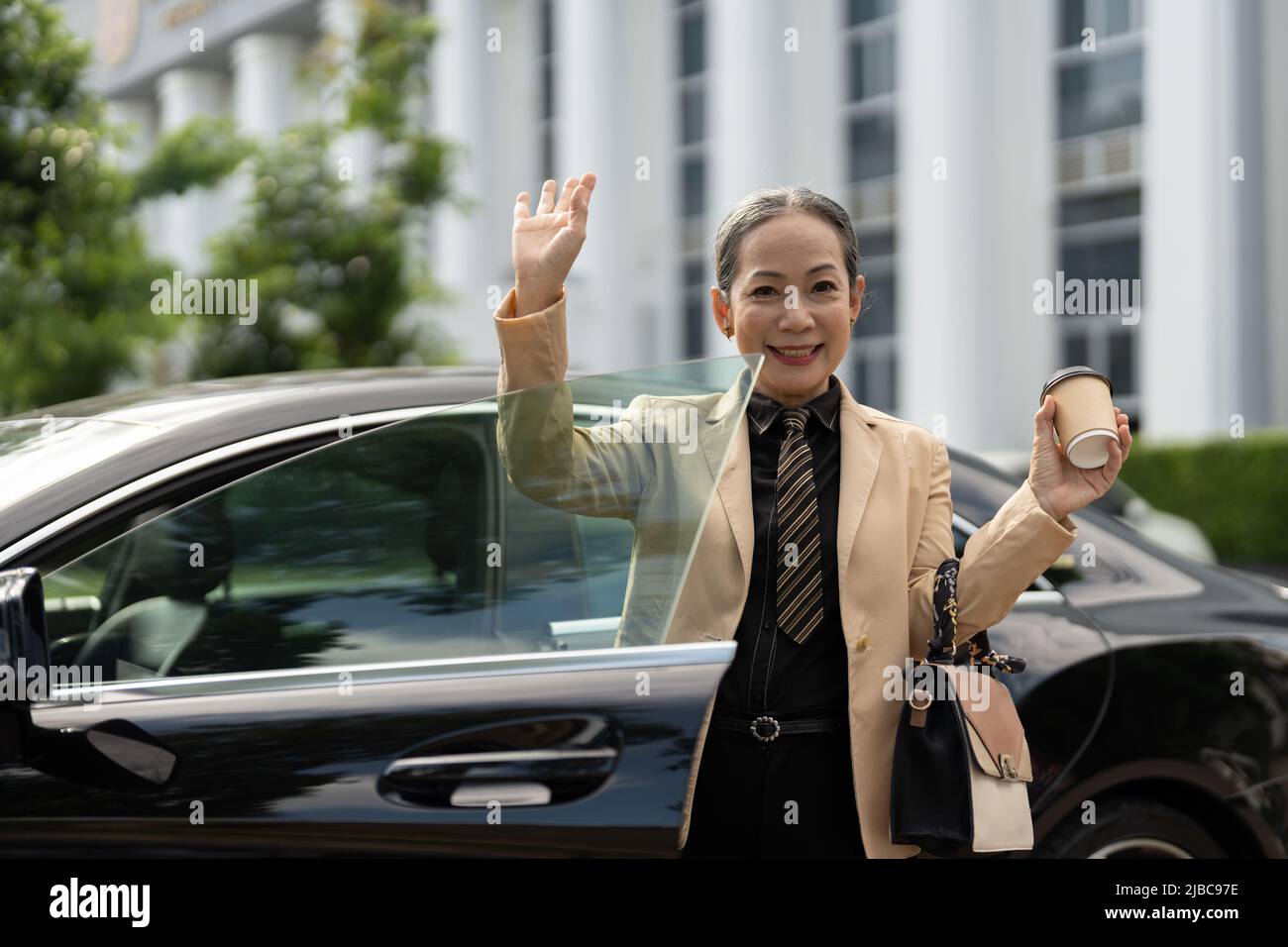 Gentile signora asiatica anziana che dice ciao, agitando la mano e ...