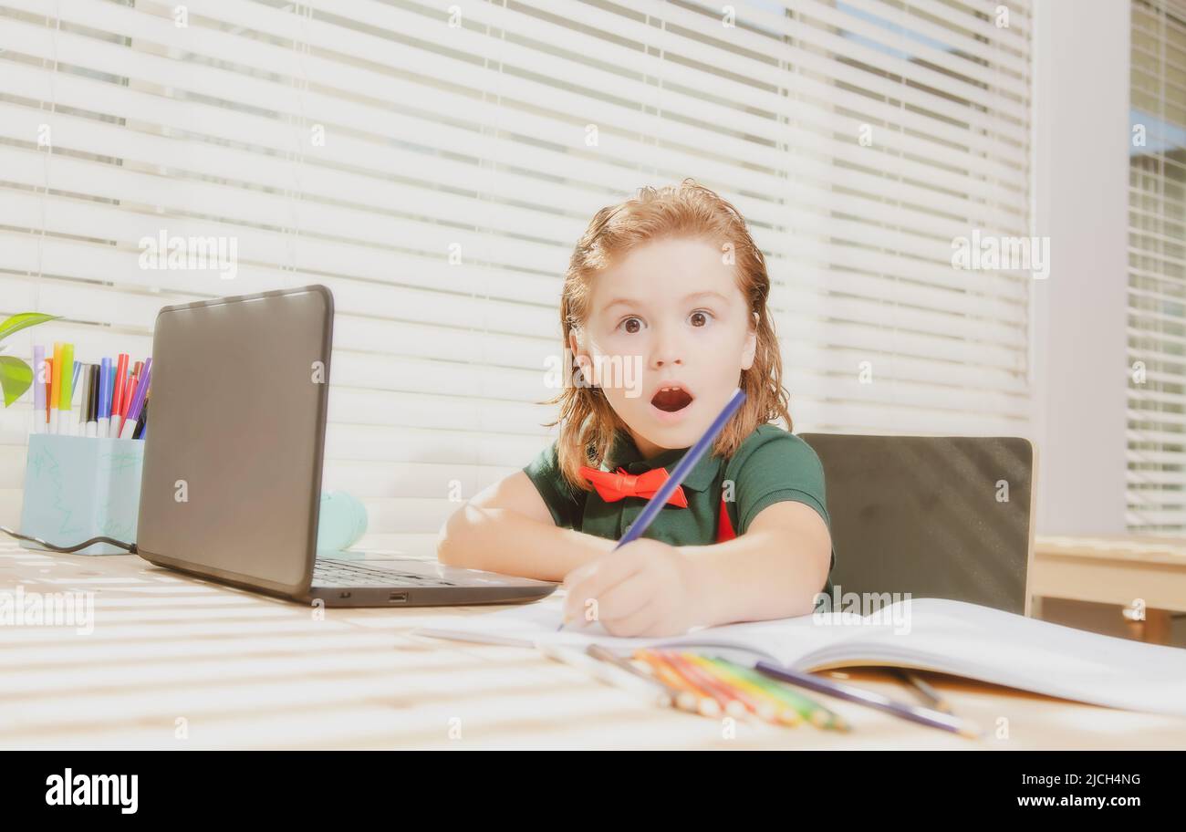 Stupito scolaro scrivere al taccuino in classe alla scuola elementare ...