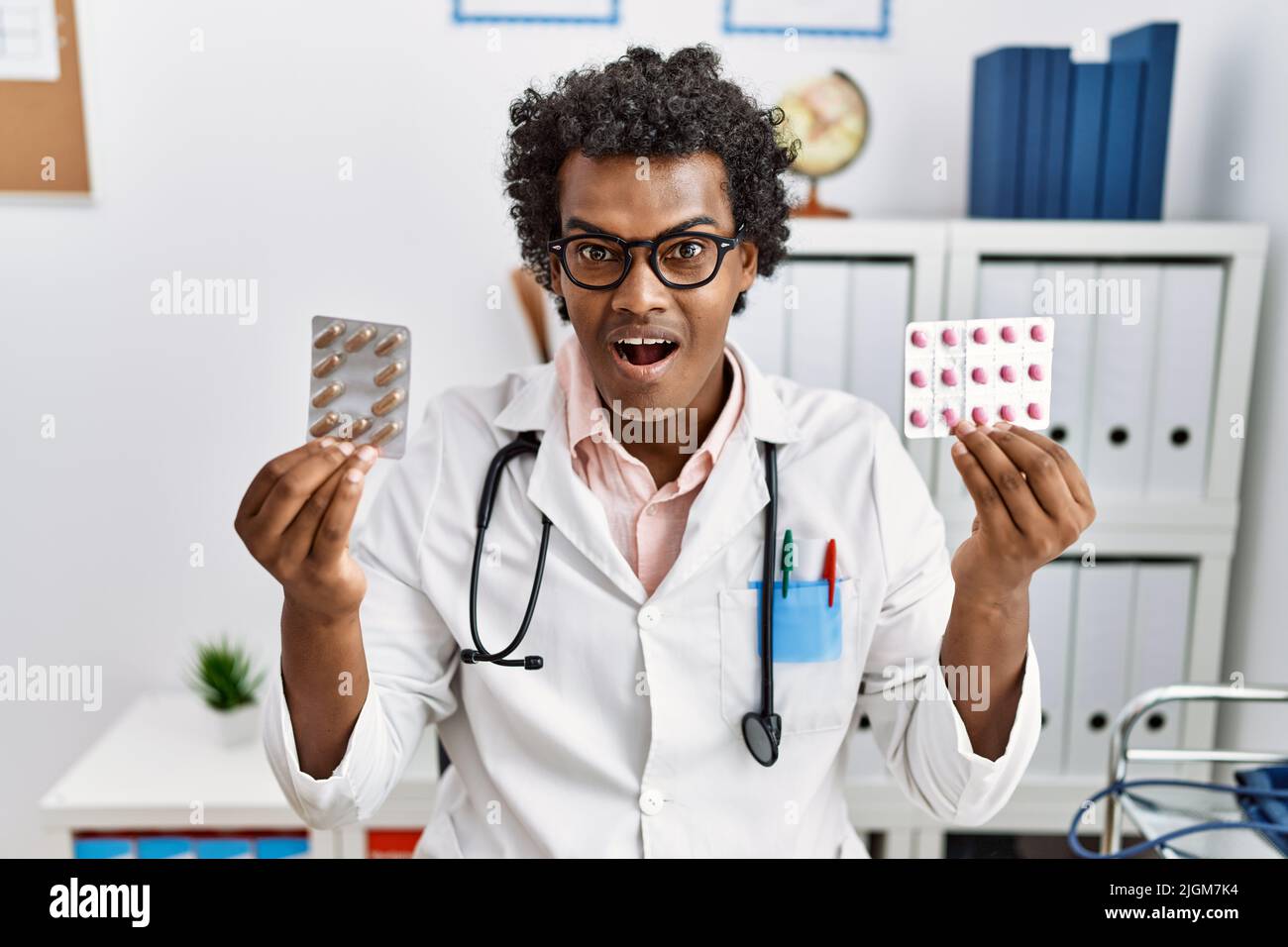 L'uomo africano che indossa medico uniforme che tiene pillole di ...