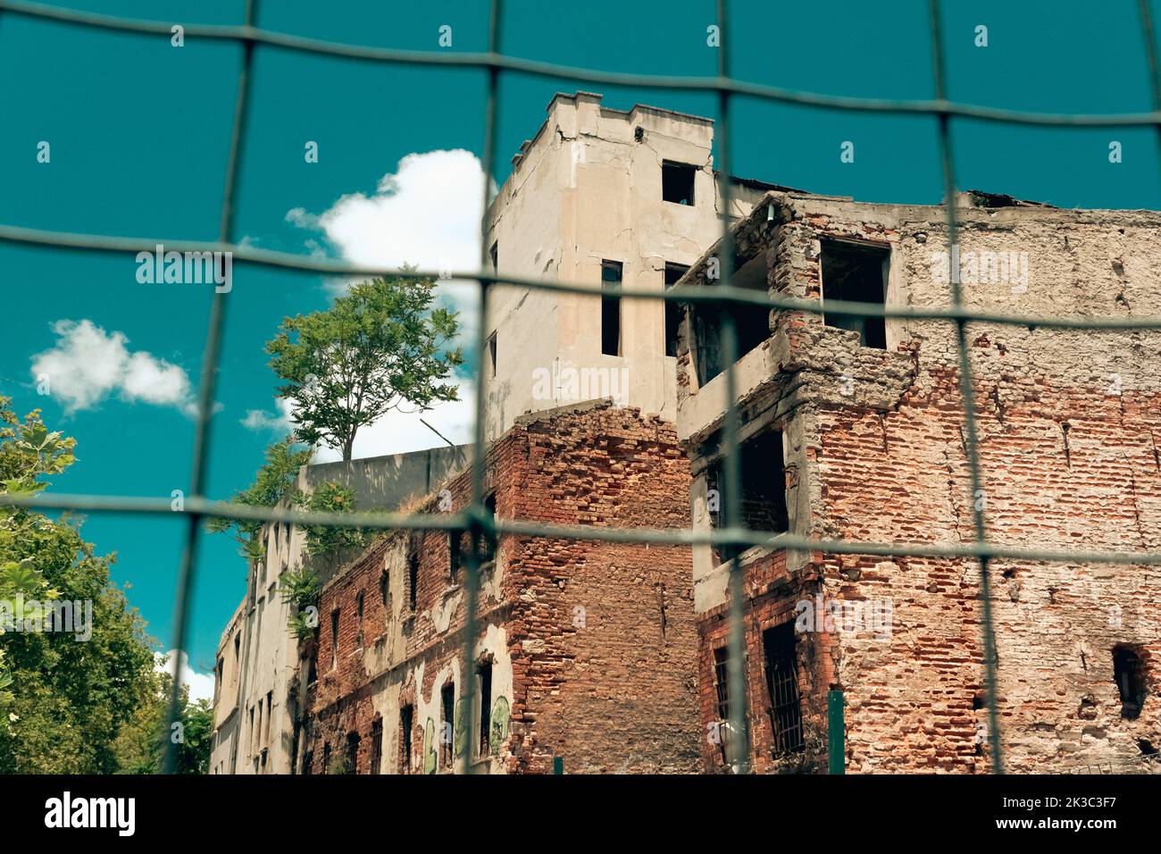 Vecchio edificio in mattoni dietro la recinzione di filo, cielo ...
