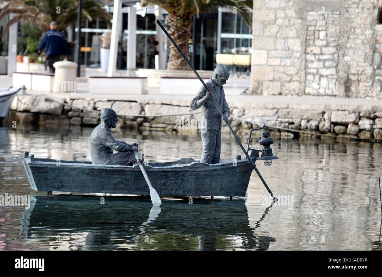 Un monumento in bronzo di pescatori è visto sulla superficie del mare ...