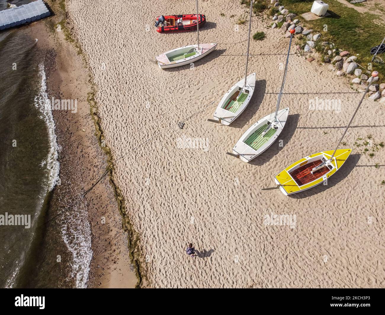 Barche a vela sulla spiaggia sabbiosa di fronte a un mucchio di alghe e ...