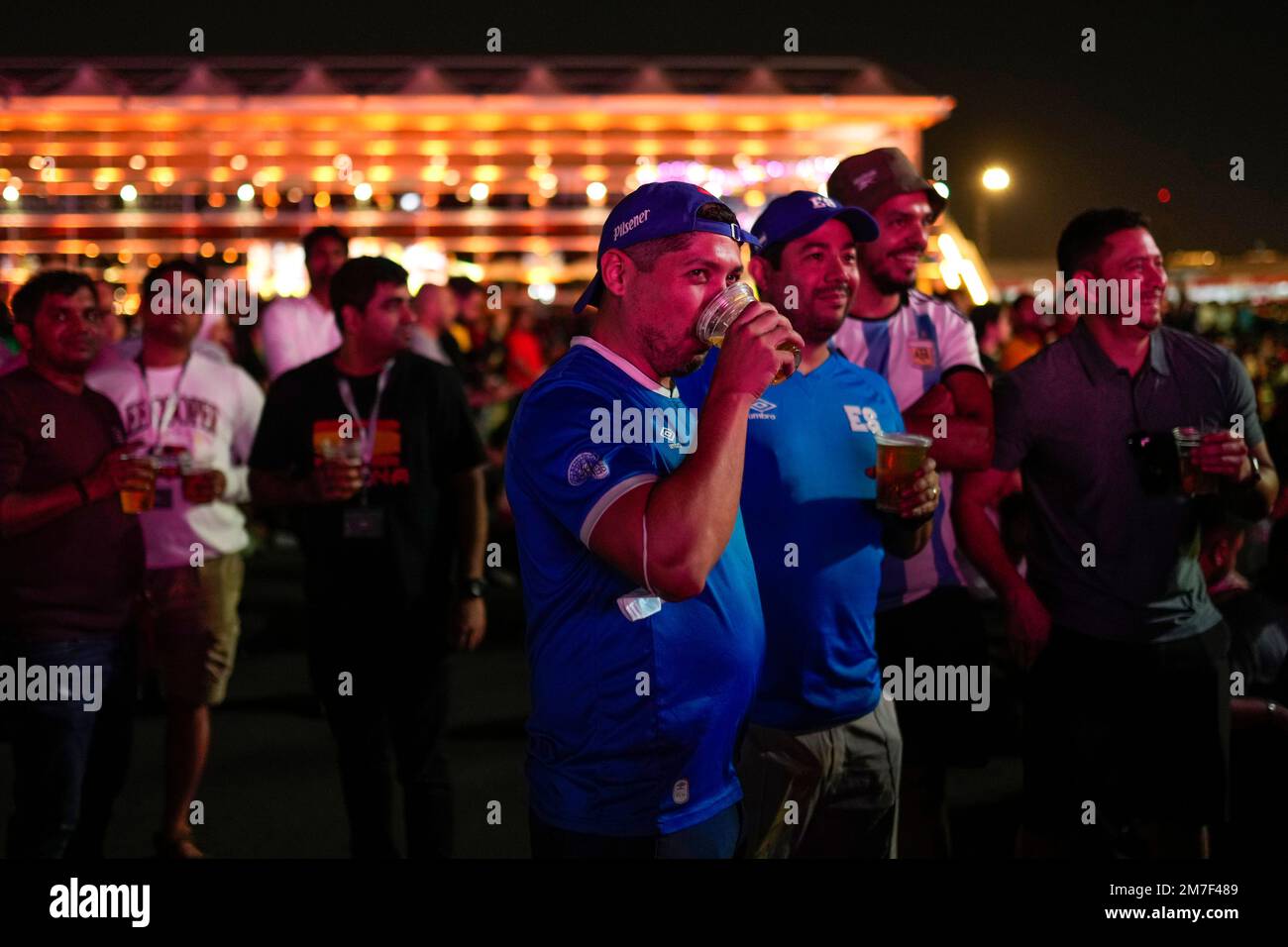 FILE - People drink beers as they watch in a giant screen at the fan ...