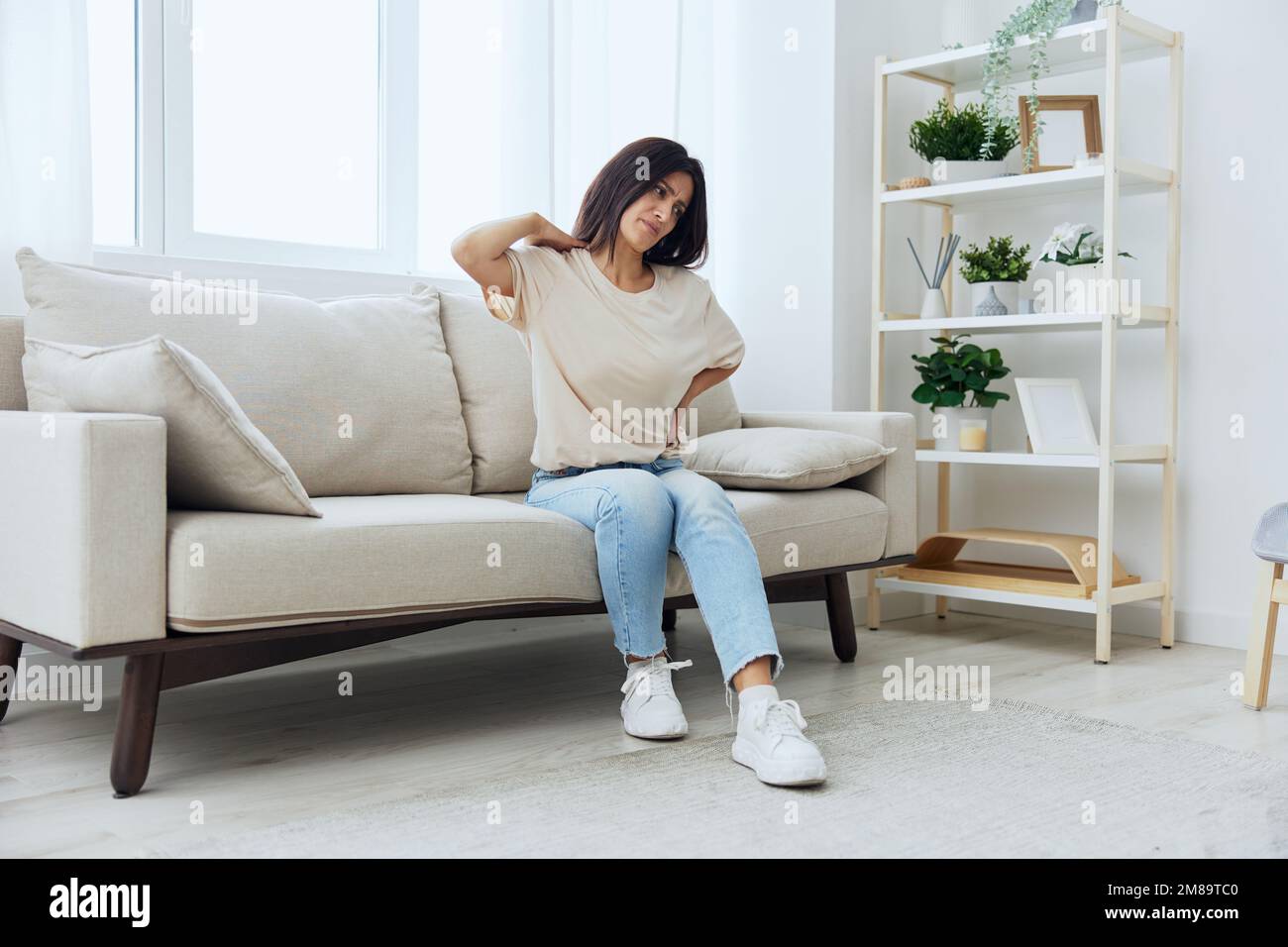 Donna seduta sul divano a casa schiena e dolore lombare, protrusione ...