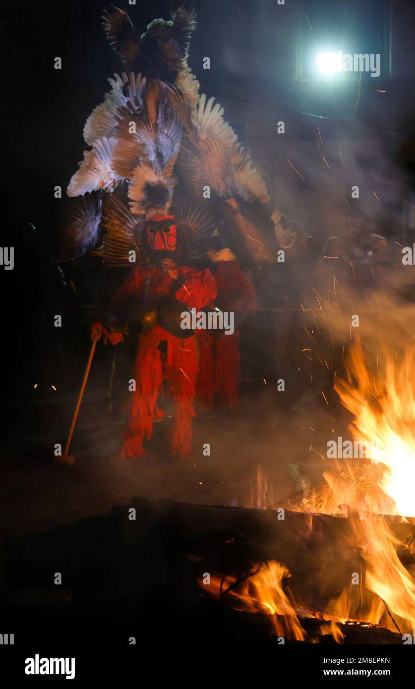 A dancer performs near bonfire carving a giant mask. as he performs an ...