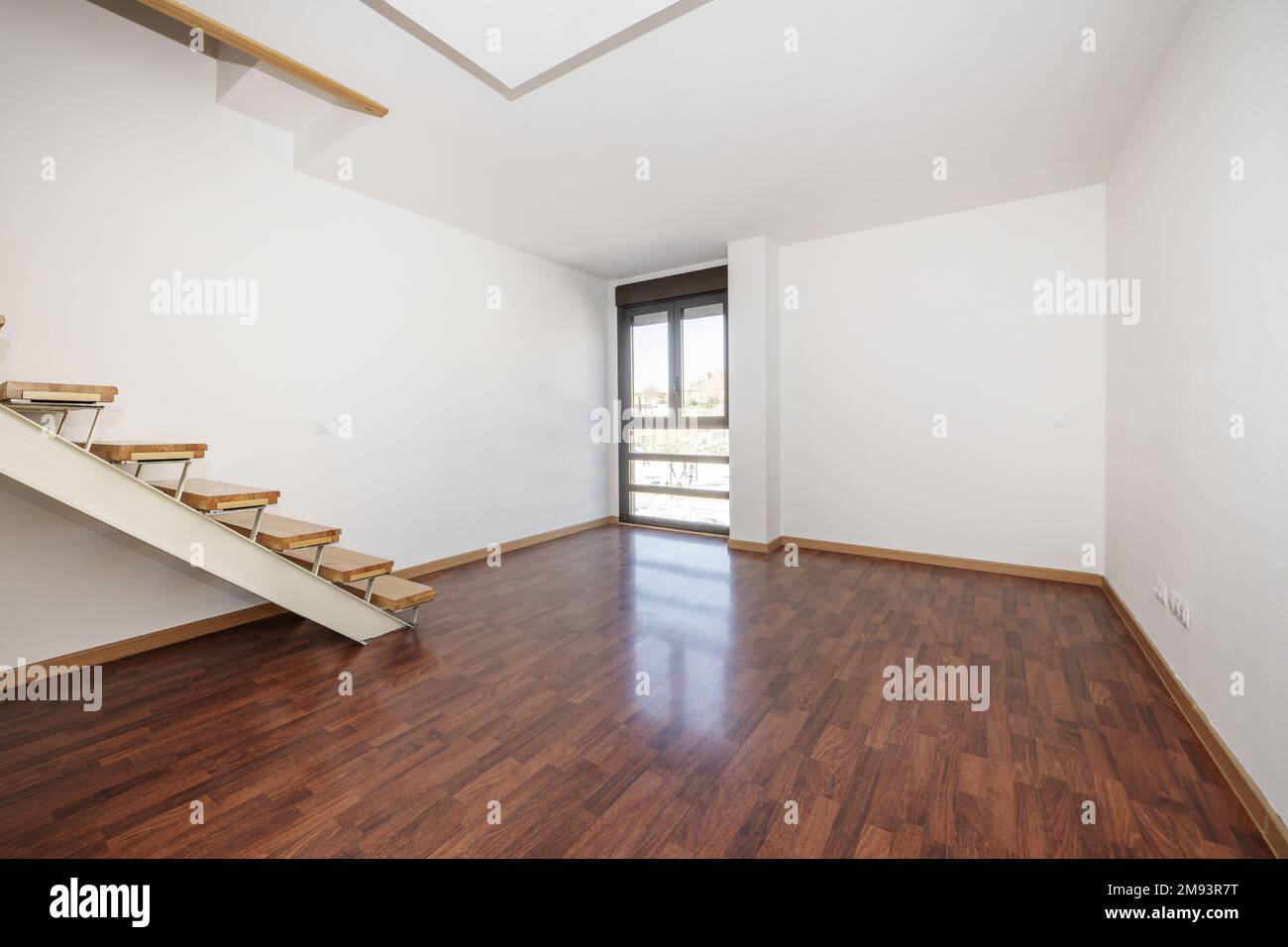 Camera vuota di un loft a due piani con una scala in metallo bianco e ...