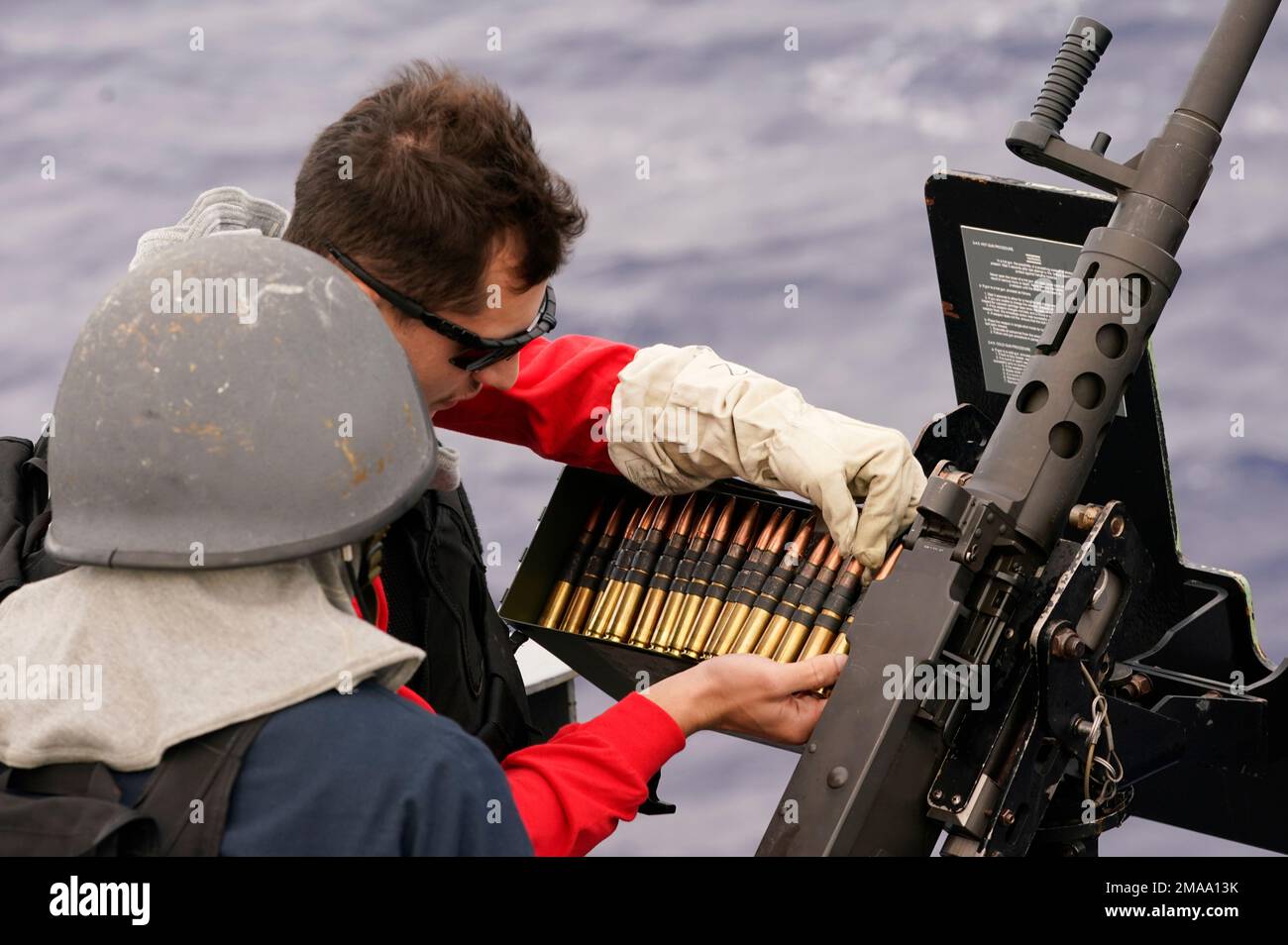 A weapons officers load a 50-caliber machine gun for a live fire drill ...