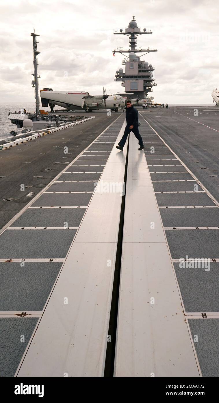 Deck personnel walk across the catapult channel aboard the nuclear ...