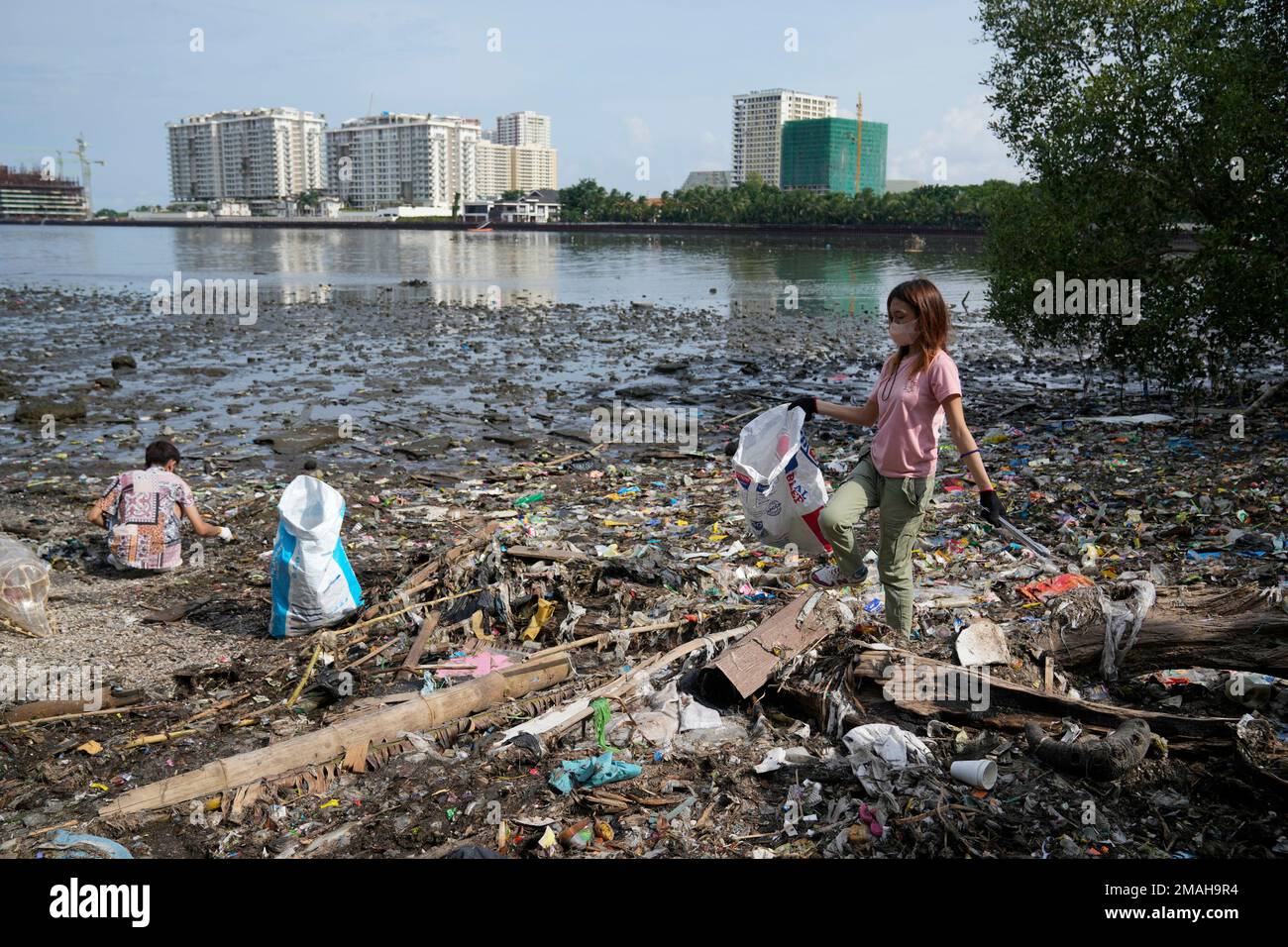 Volunteers pick up garbage along a polluted coastal area in Metro ...