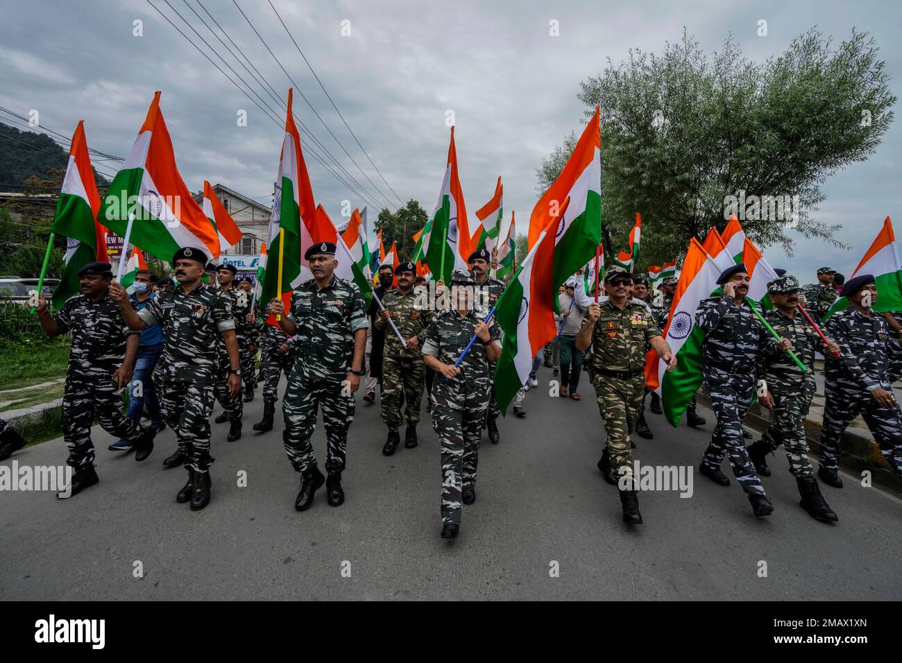 Indian paramilitary officers hold national flags as they march in a ...
