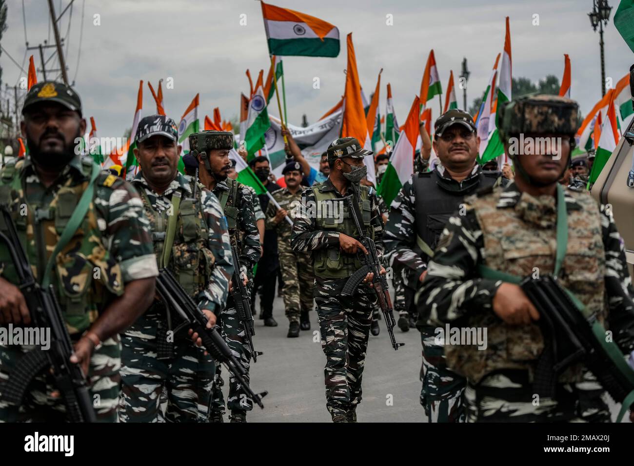 Indian paramilitary officers hold national flags as they march in a ...