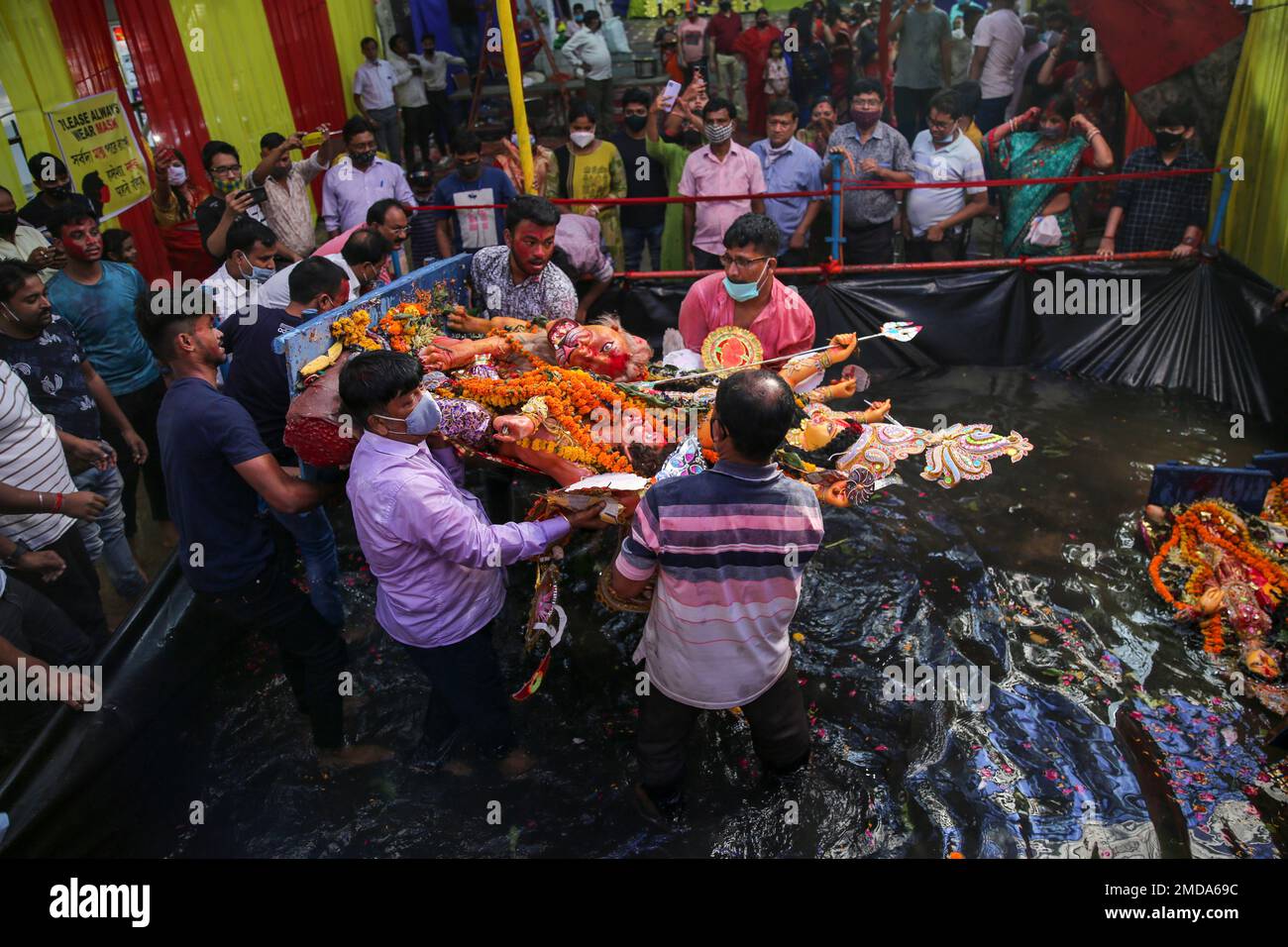 Devotees immerse an idol of Hindu goddess Durga inside a makeshift pond ...