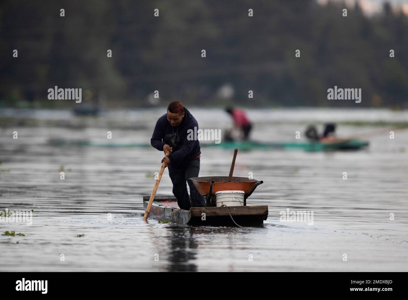 A farmer uses a pole to move his canoe to his floating farm known as ...