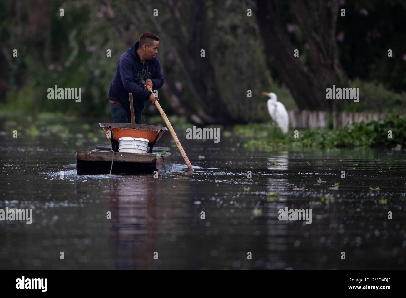 A farmer uses a pole to move his boat to his floating farm known as ...