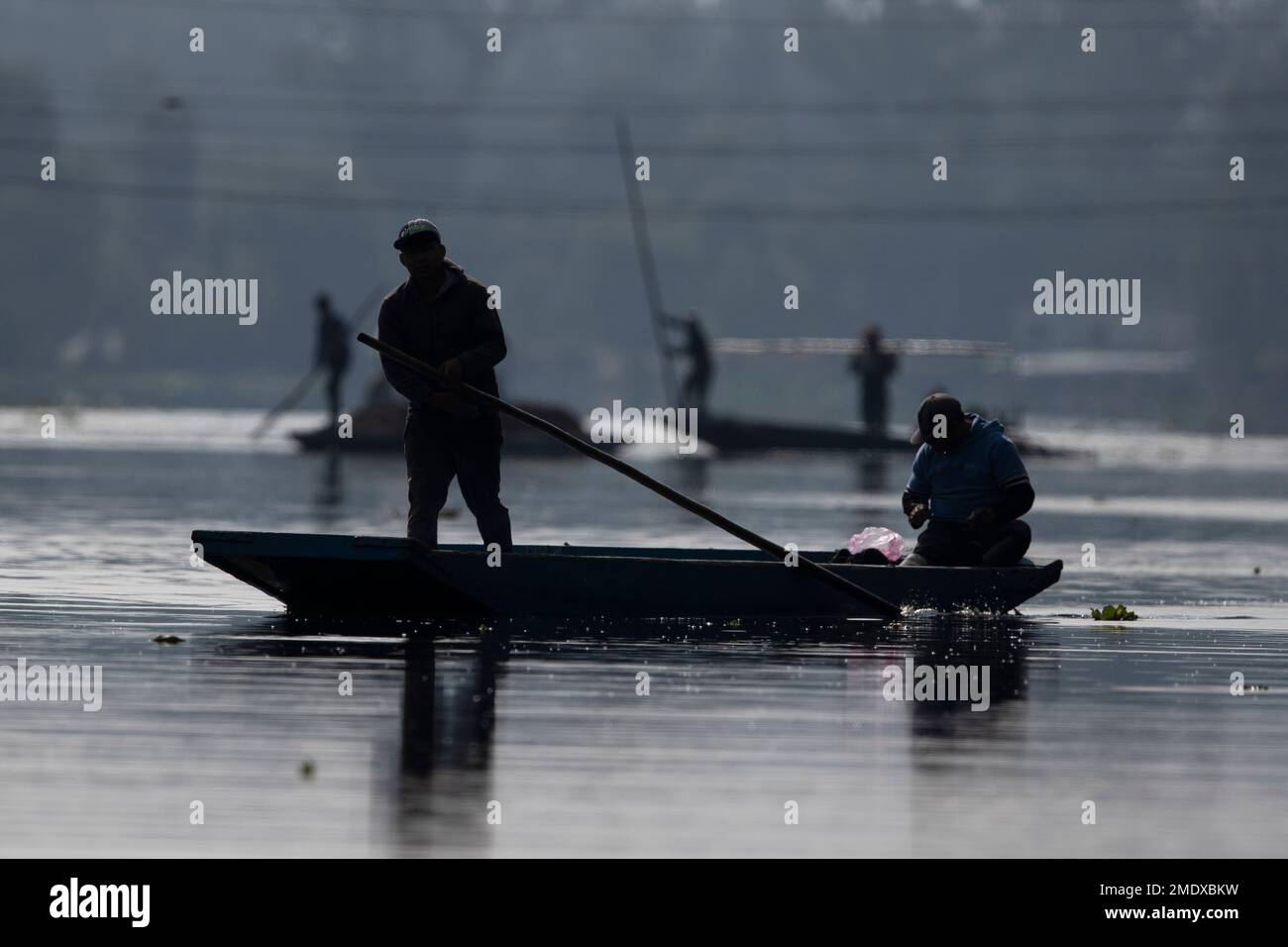A farmer uses a pole to move his canoe to his floating farm known as ...