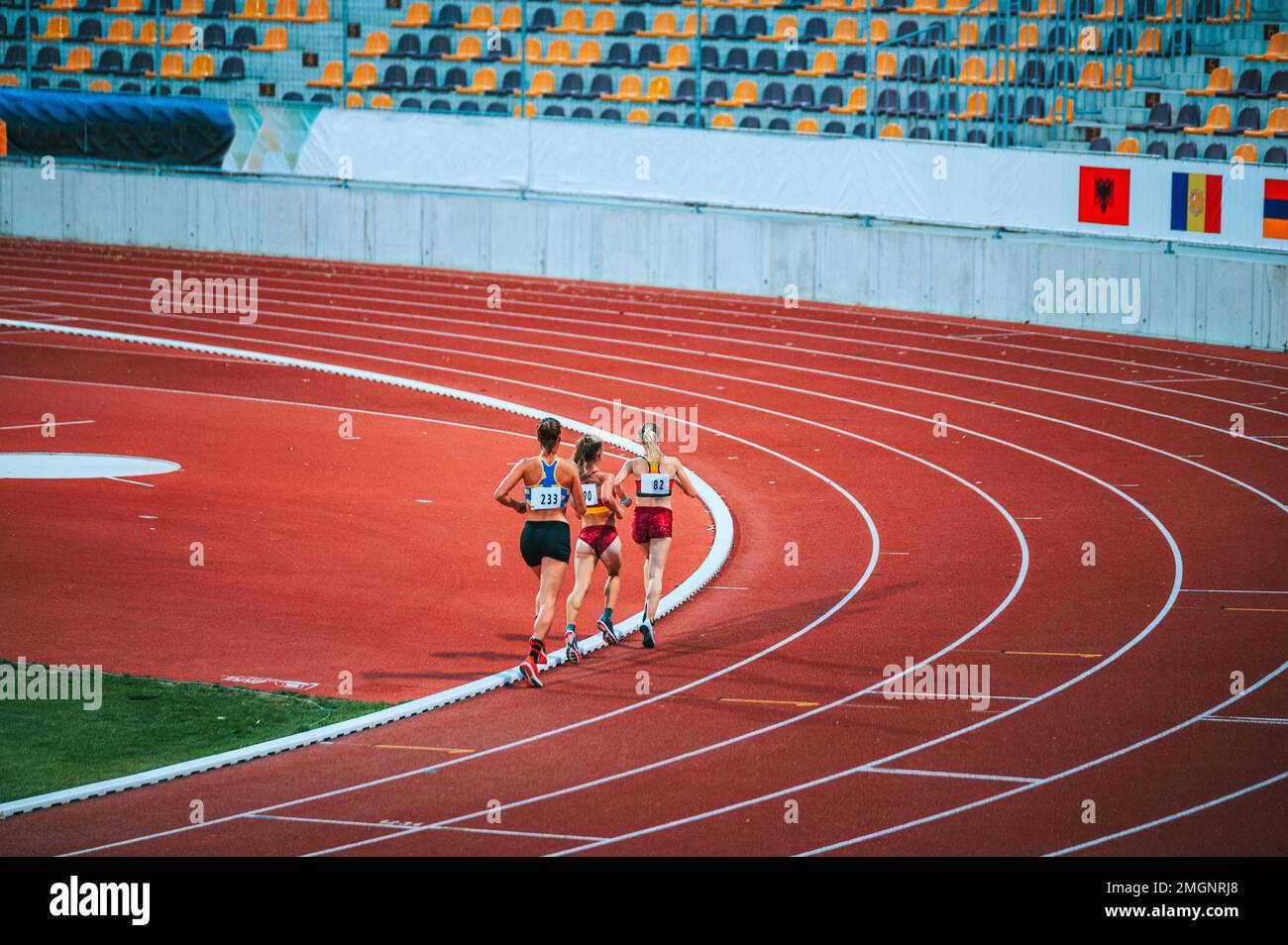 Le gambe delle atlete determinate spingono attraverso la corsa 5000m in pista, mostrando il loro ...