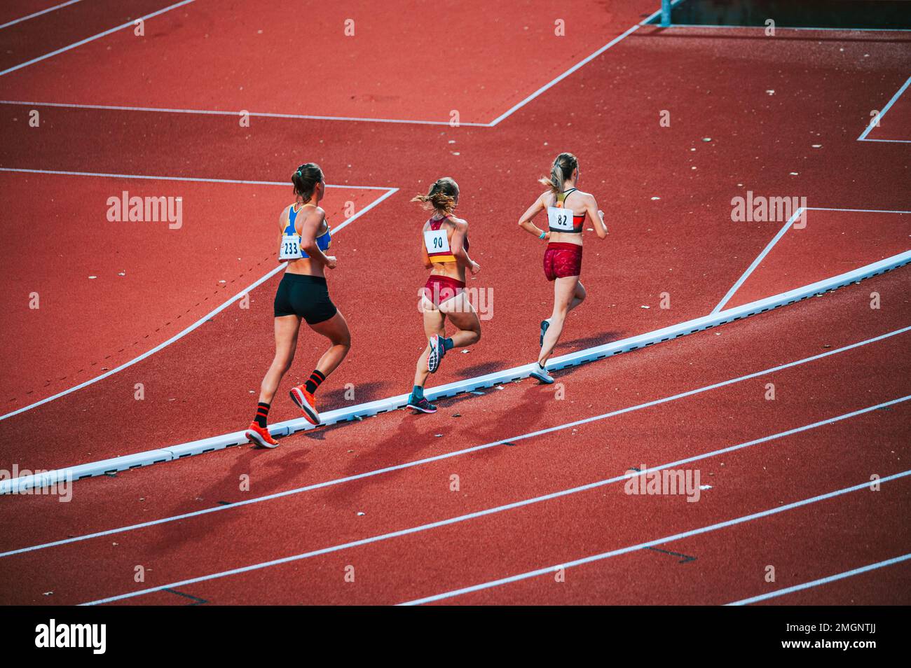 Le gambe delle atlete determinate spingono attraverso la corsa 5000m in pista, mostrando il loro ...