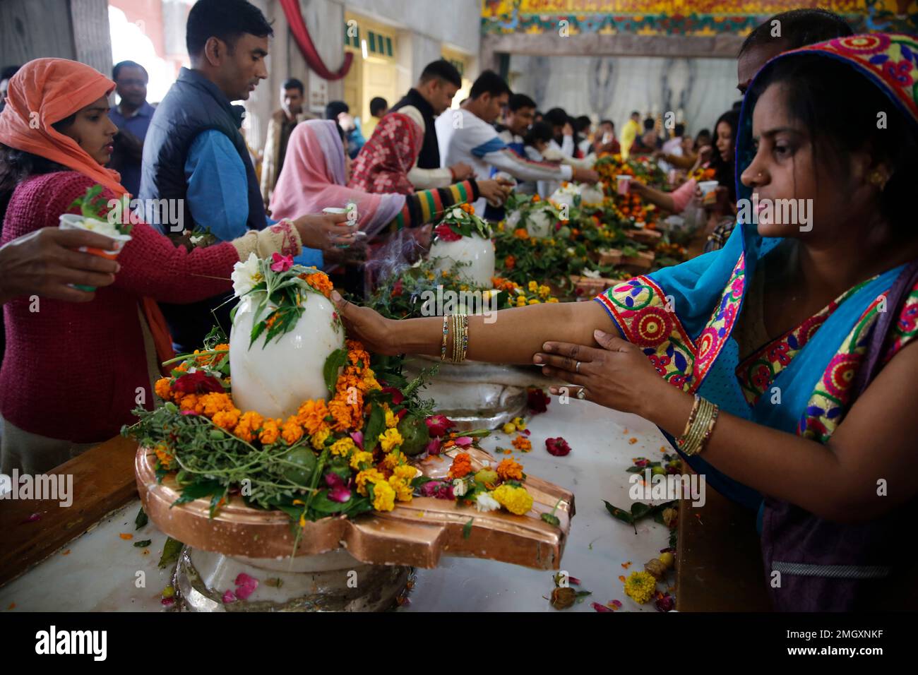 Indian Hindu devotees offer prayer at a row of Shivlings, idols ...