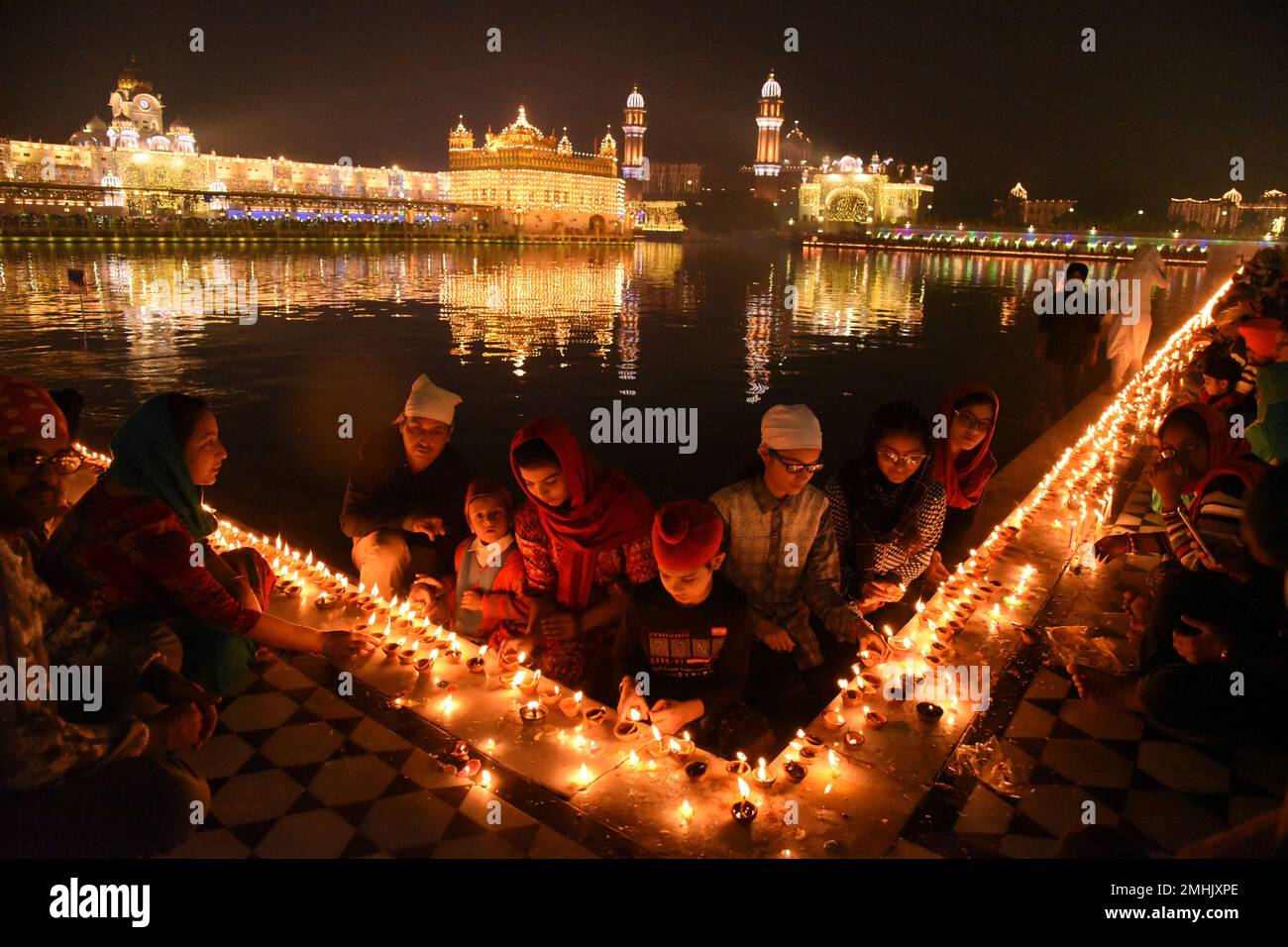 Sikh devotees light candles at the illuminated Golden Temple, the holiest of Sikh shrines, on ...