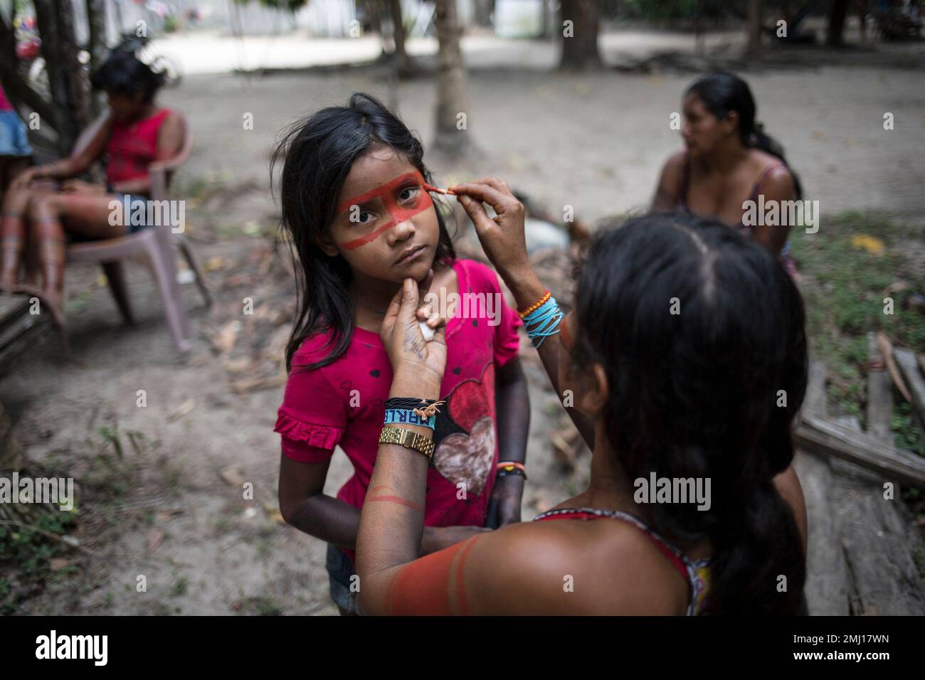 In this Sept. 4, 2019 photo, a child stands still as a woman paints a ...