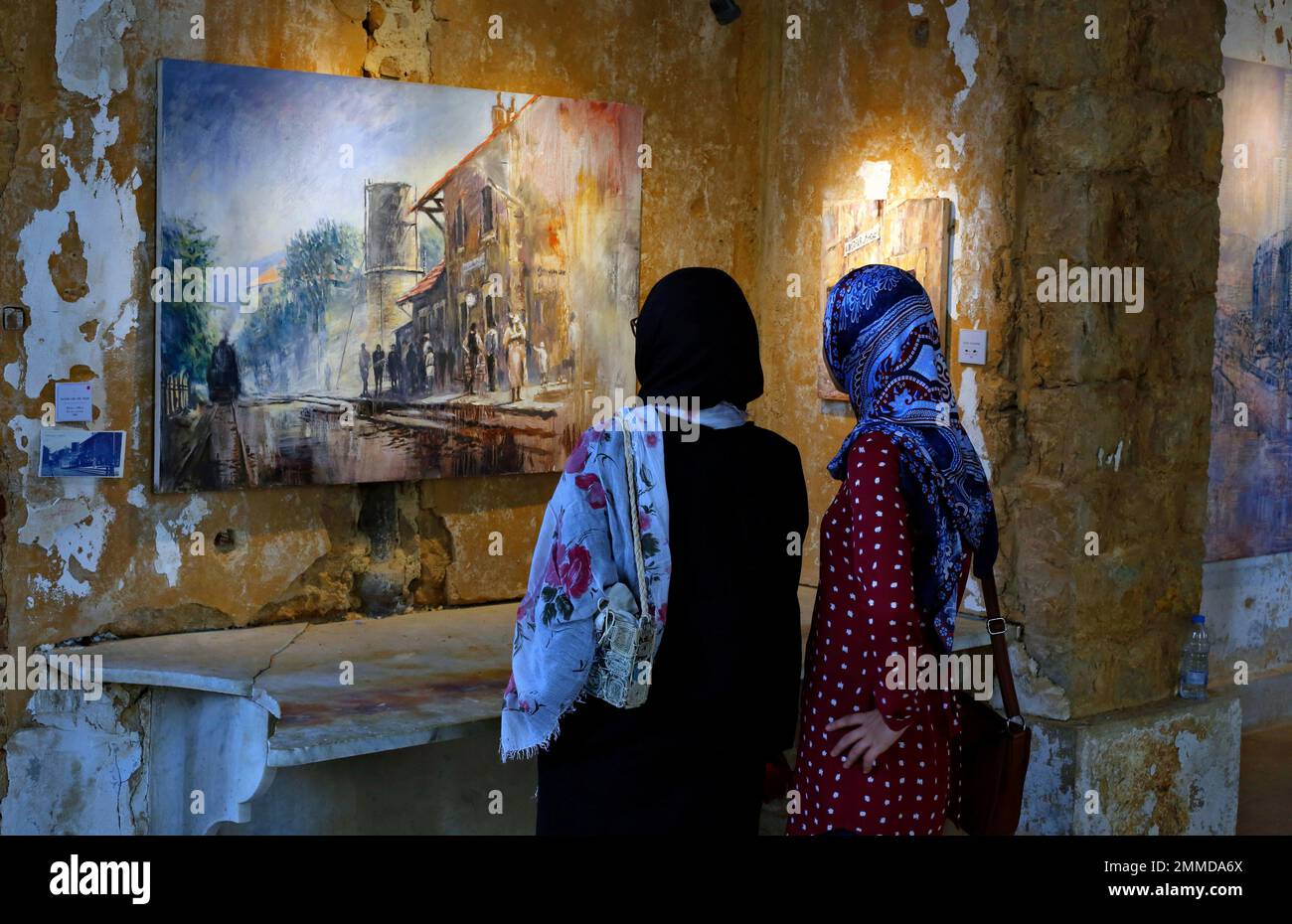 Visitors look at a painting during an exhibition at the Sawfar Grand ...