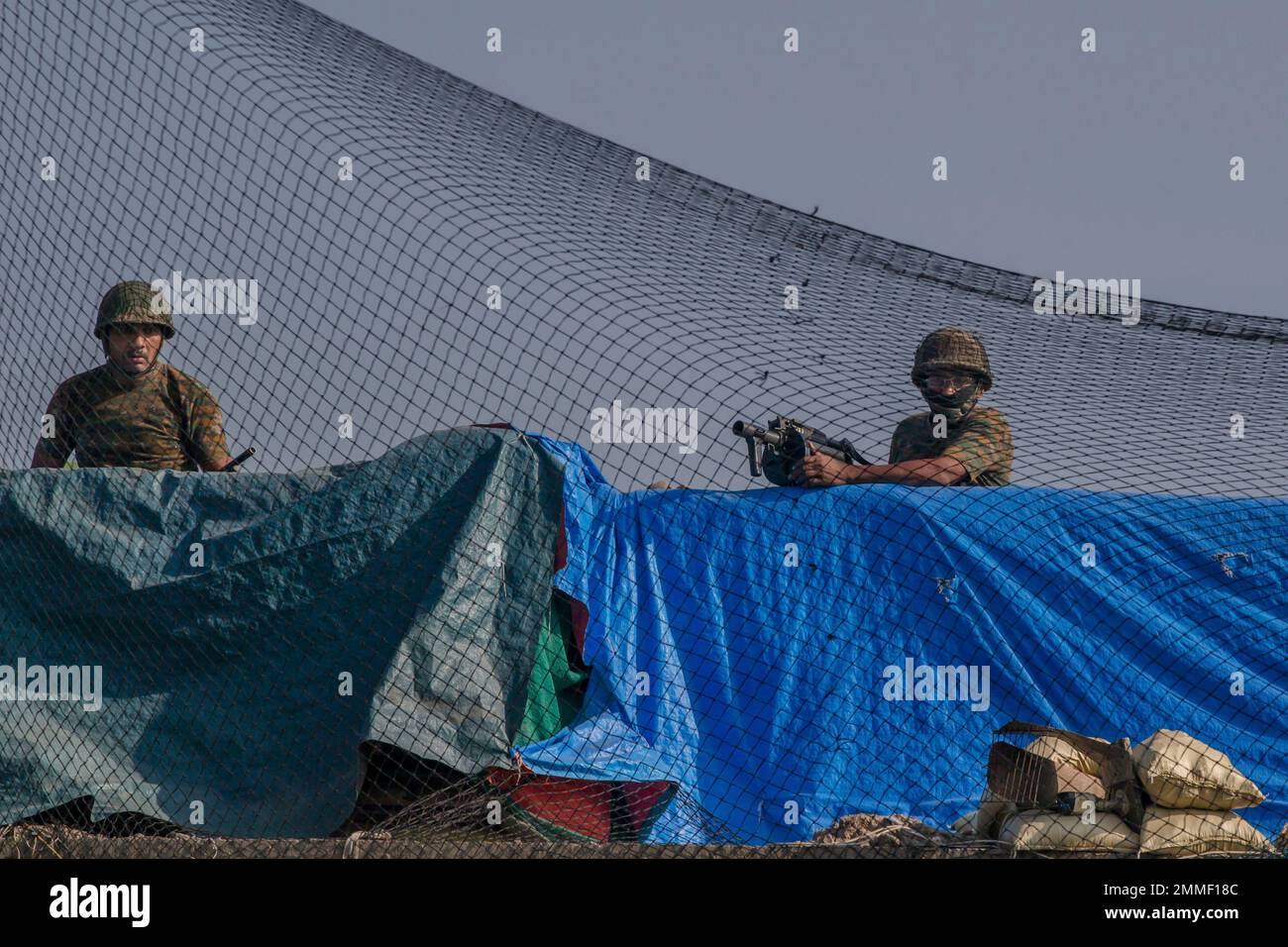 Indian paramilitary soldiers take position on the roof of their base as ...