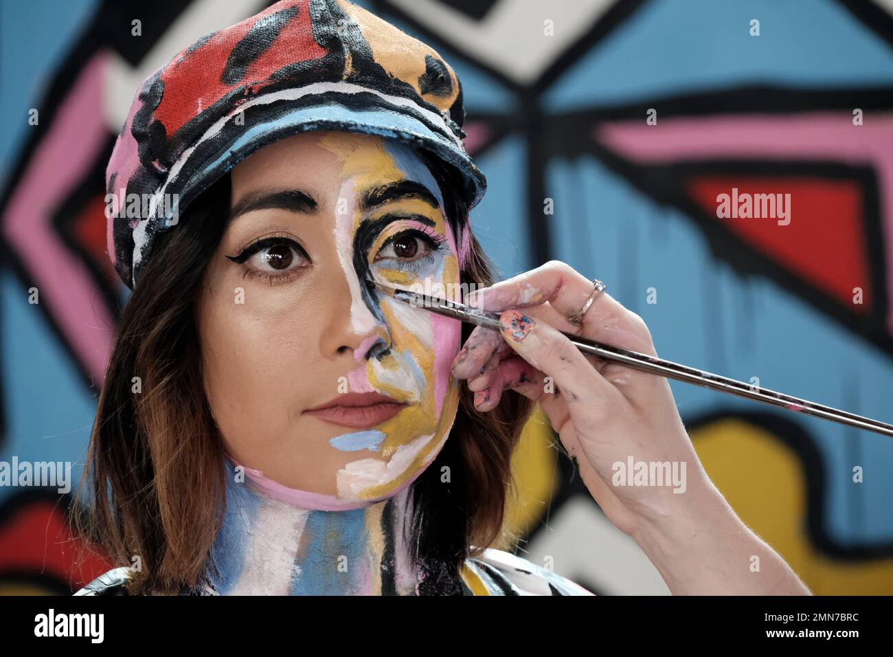 Artist Alexa Meade, right, paints the face of model Justine Jaime ...