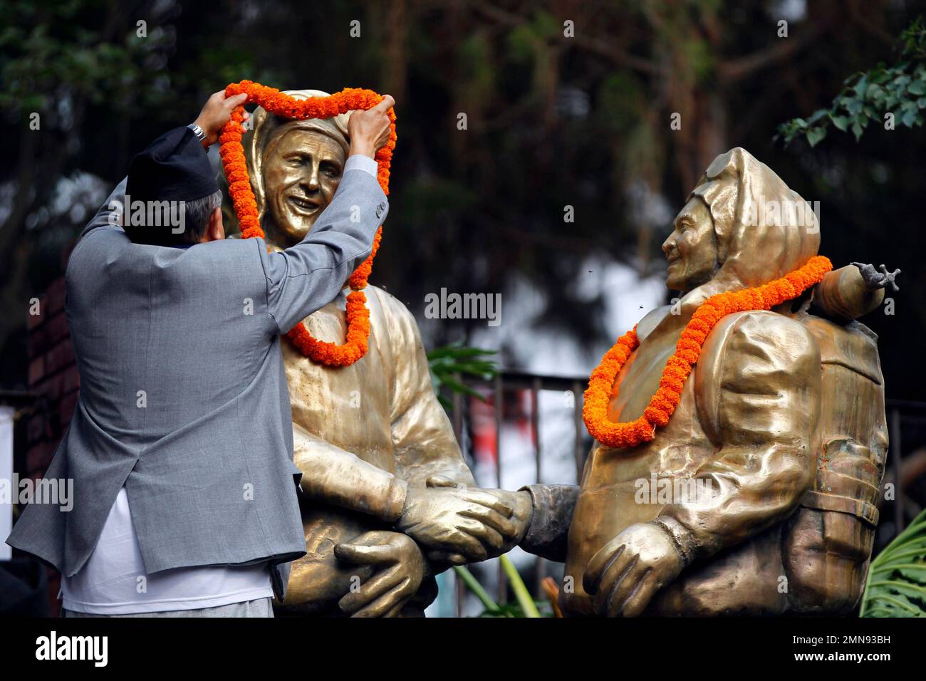 A man puts a garland around the statues of New Zealander Edmund Hillary ...