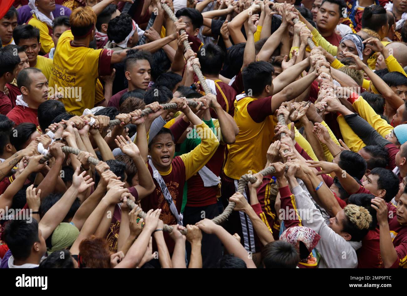 Filipino Roman Catholic devotees jostle to grab the rope pulling the ...