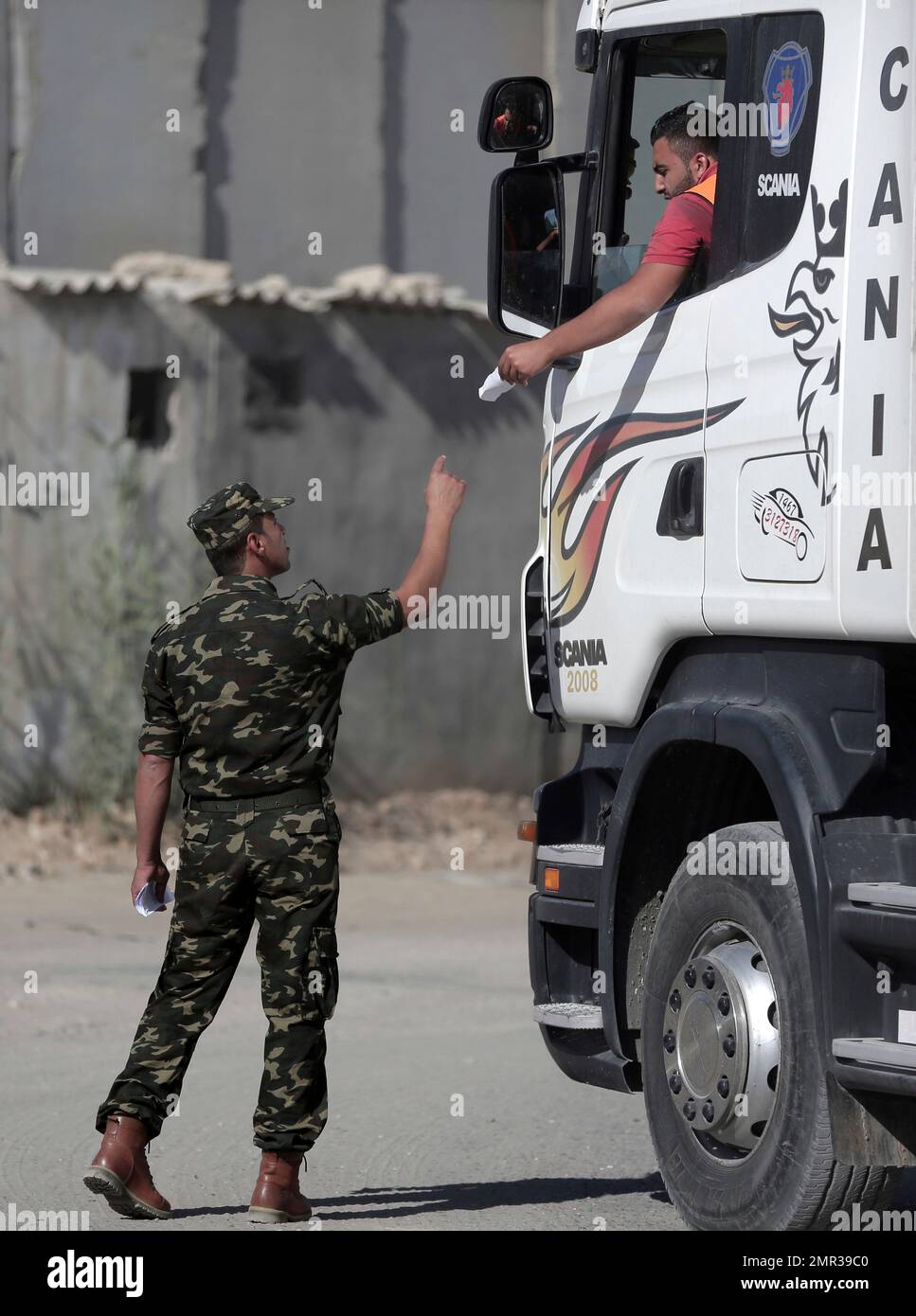 A Palestinian security officer controls traffic of imported goods at ...