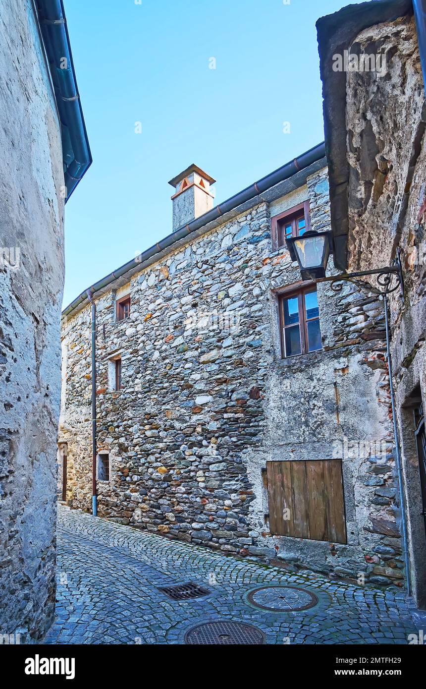 Cammina lungo la stretta salita curva, fiancheggiata da case medievali ...