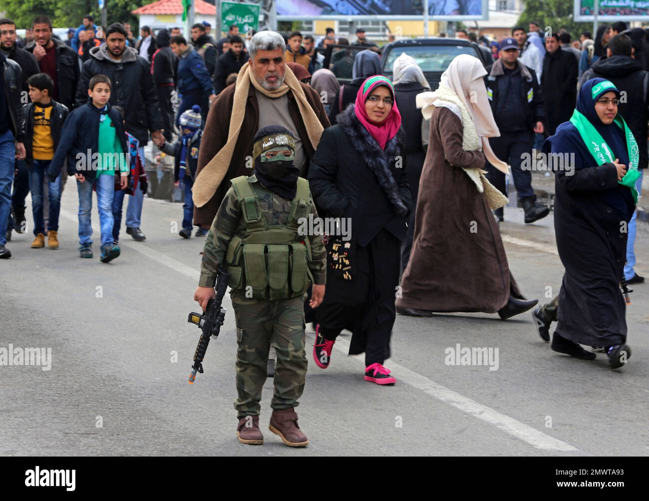 A masked Palestinian boy wears a uniform and holds a toy weapon during ...