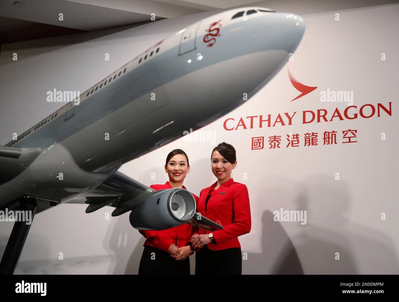 Flight attendants pose next to a model jet decorated in the new livery ...