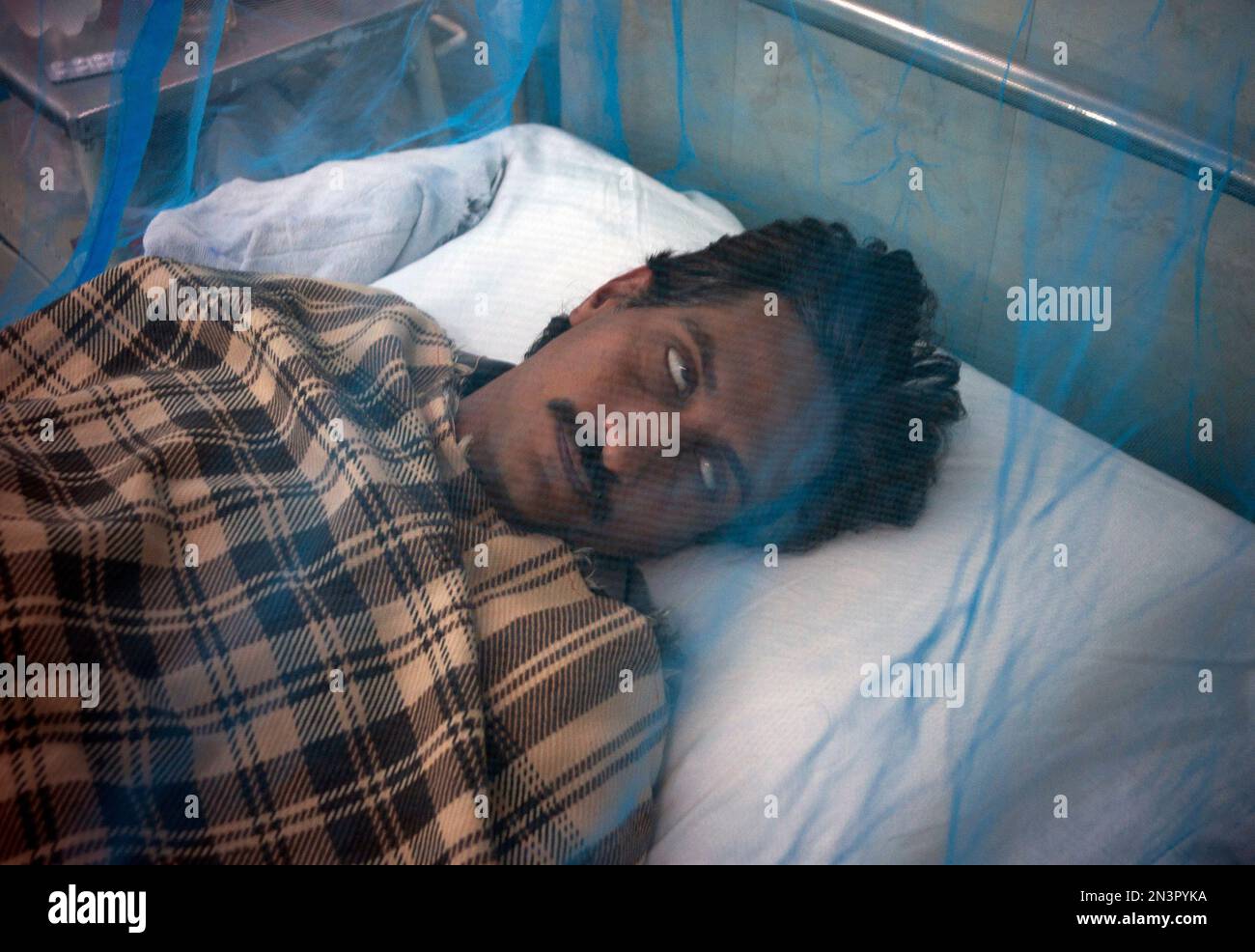 A Pakistani patient suffering from dengue fever rests in an isolation ...