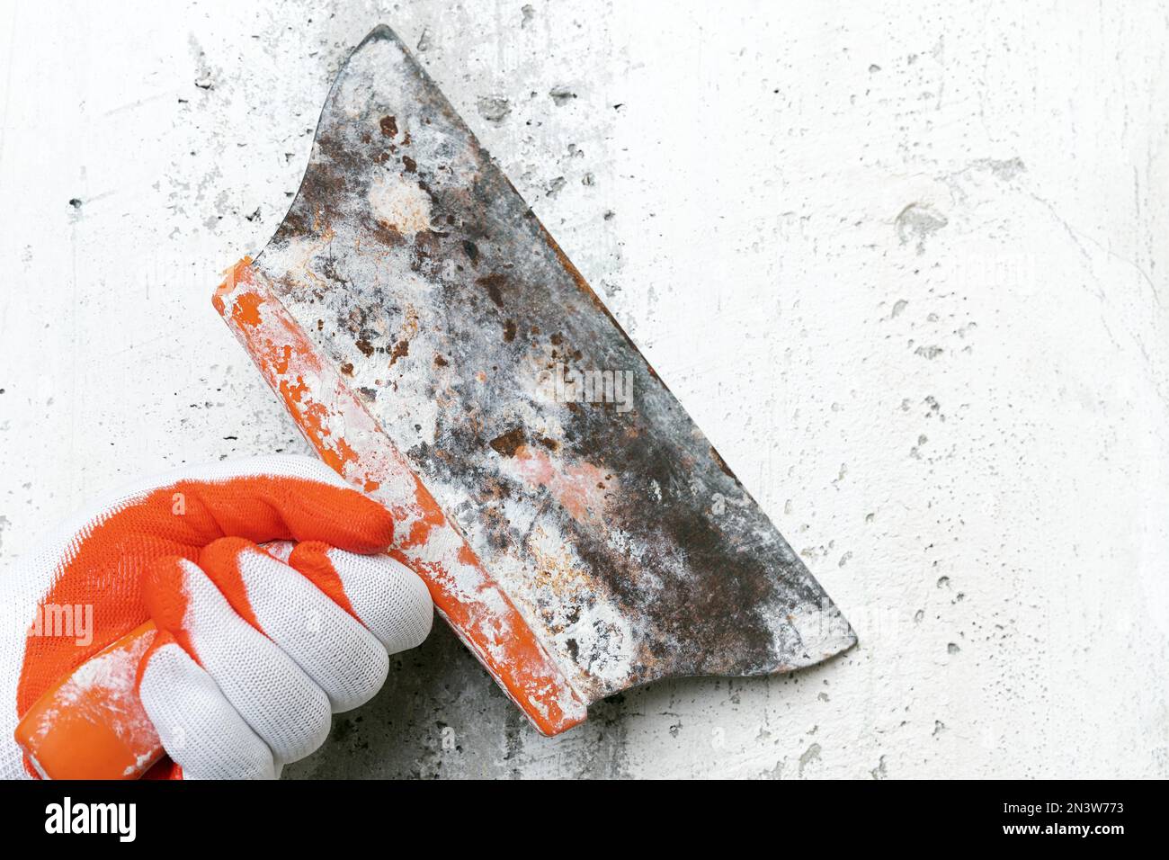 Mano irriconoscibile di intonaco tiene un vecchio coltello di stucco ...