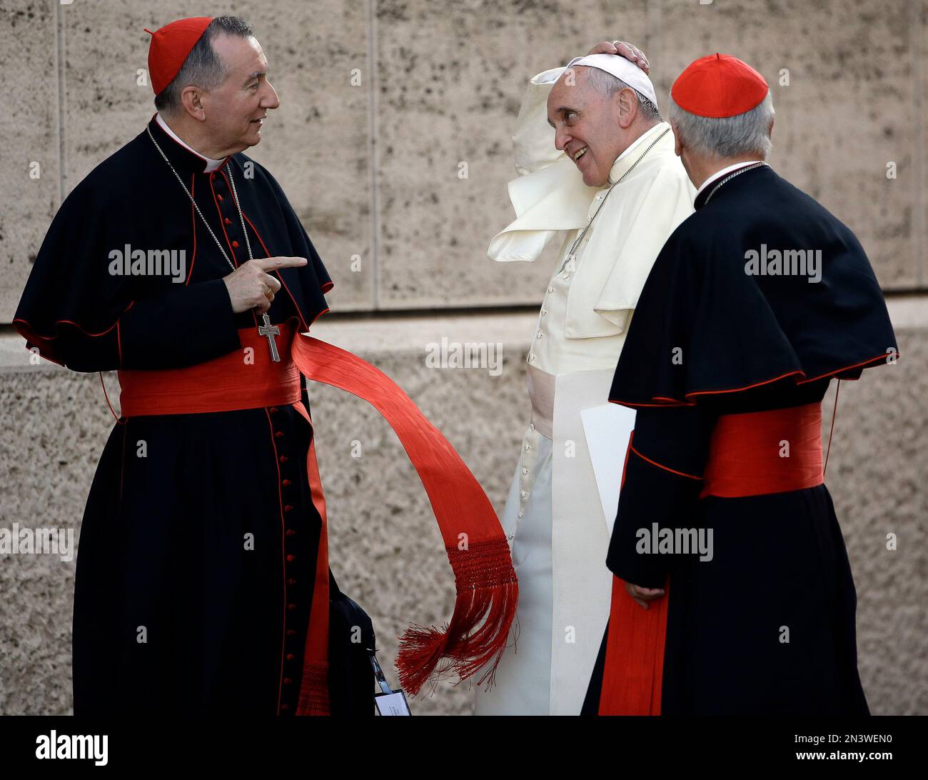 Pope Francis adjusts his skullcap as he talks with Vatican Secretary of ...