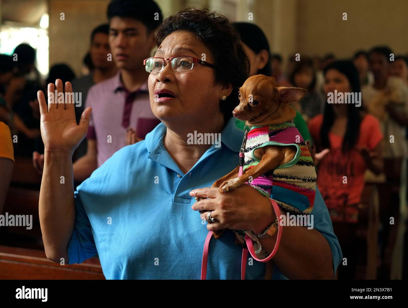 A Filipino pet owner carries her dog as she prays before the animal ...