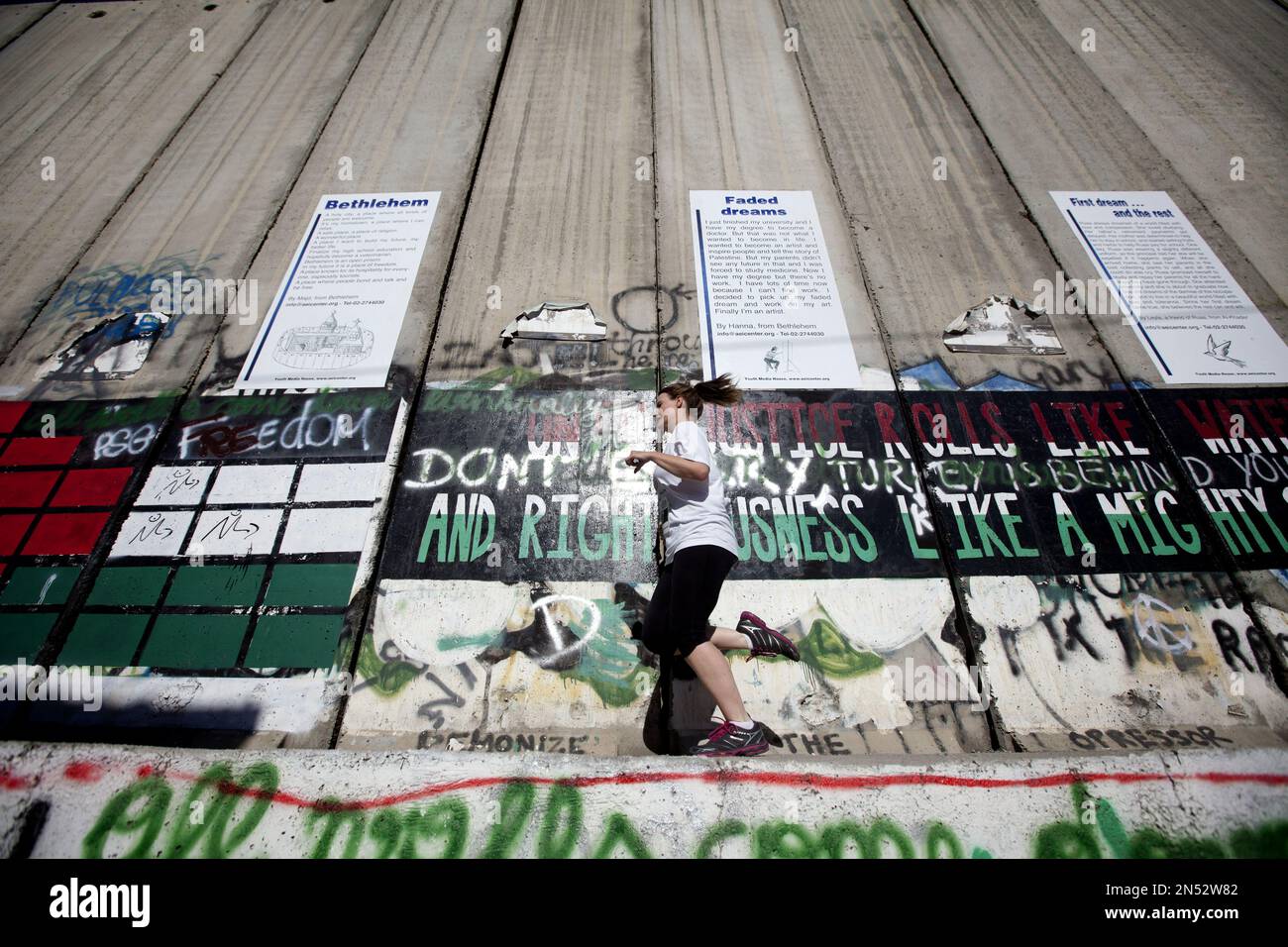 A foreign activist runs past the massive West Bank separation barrier ...