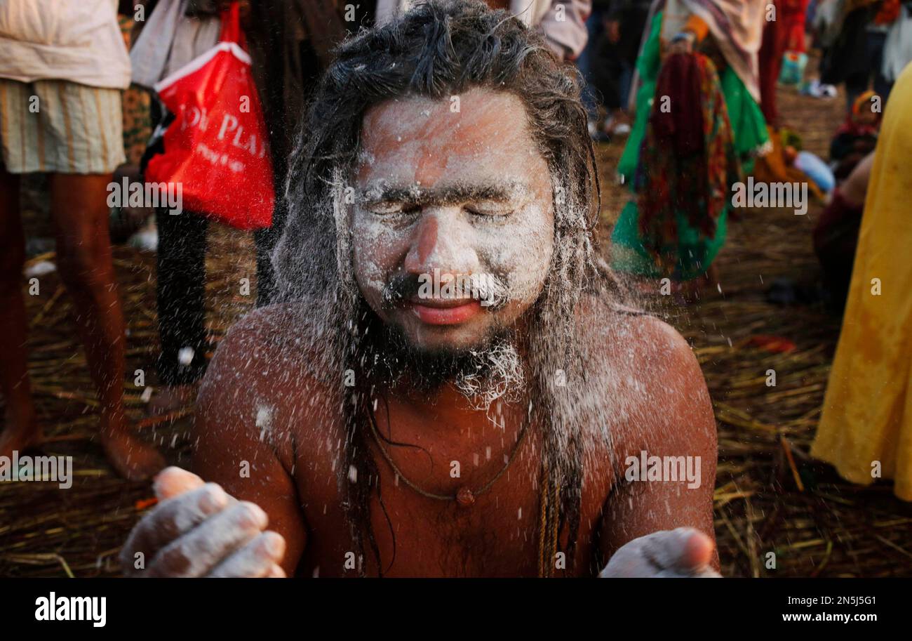 A Sadhu, or Hindu holy man, smears his face with ash at Sangam ...