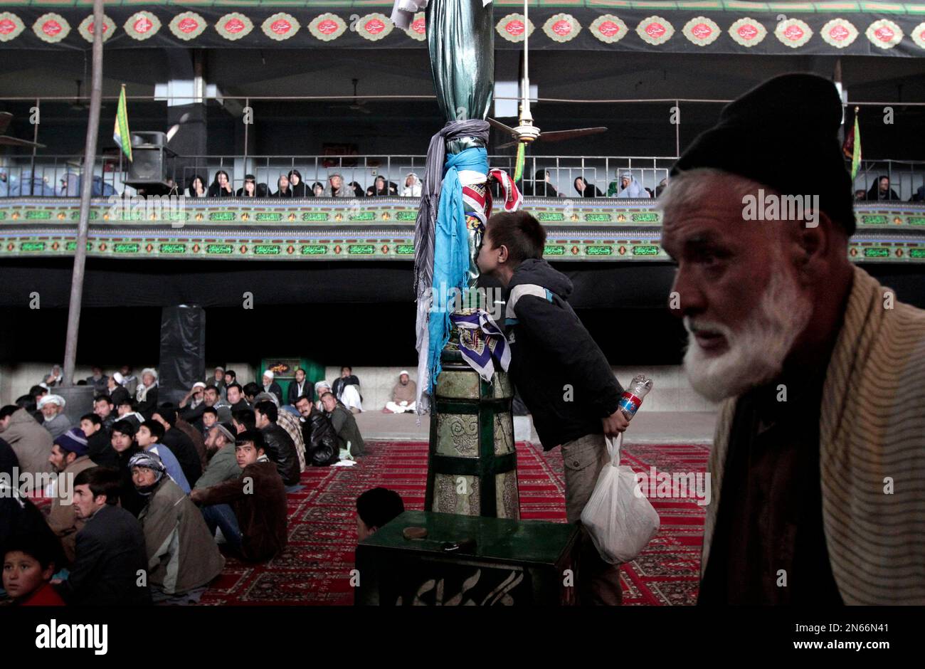 An Afghan Shiite boy kisses the holy mace for blessings during a day ...