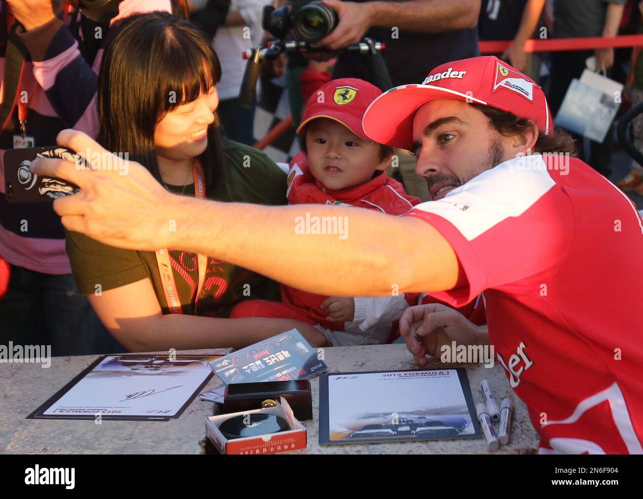 Ferrari driver Fernando Alonso of Spain takes a photo with a young fan ...