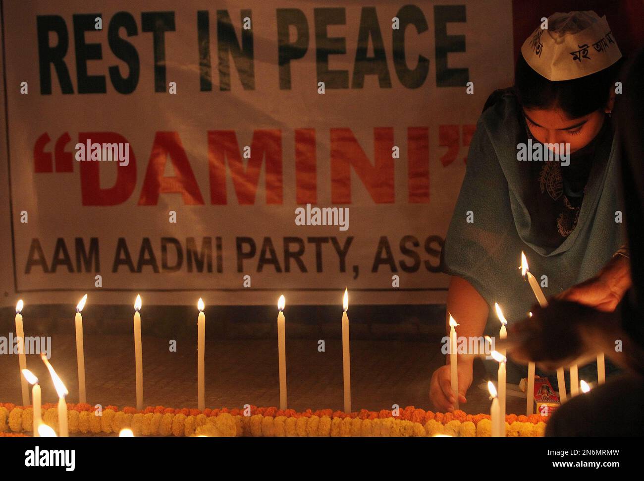 An Indian woman lights a candle to mark the verdict after a judge ...