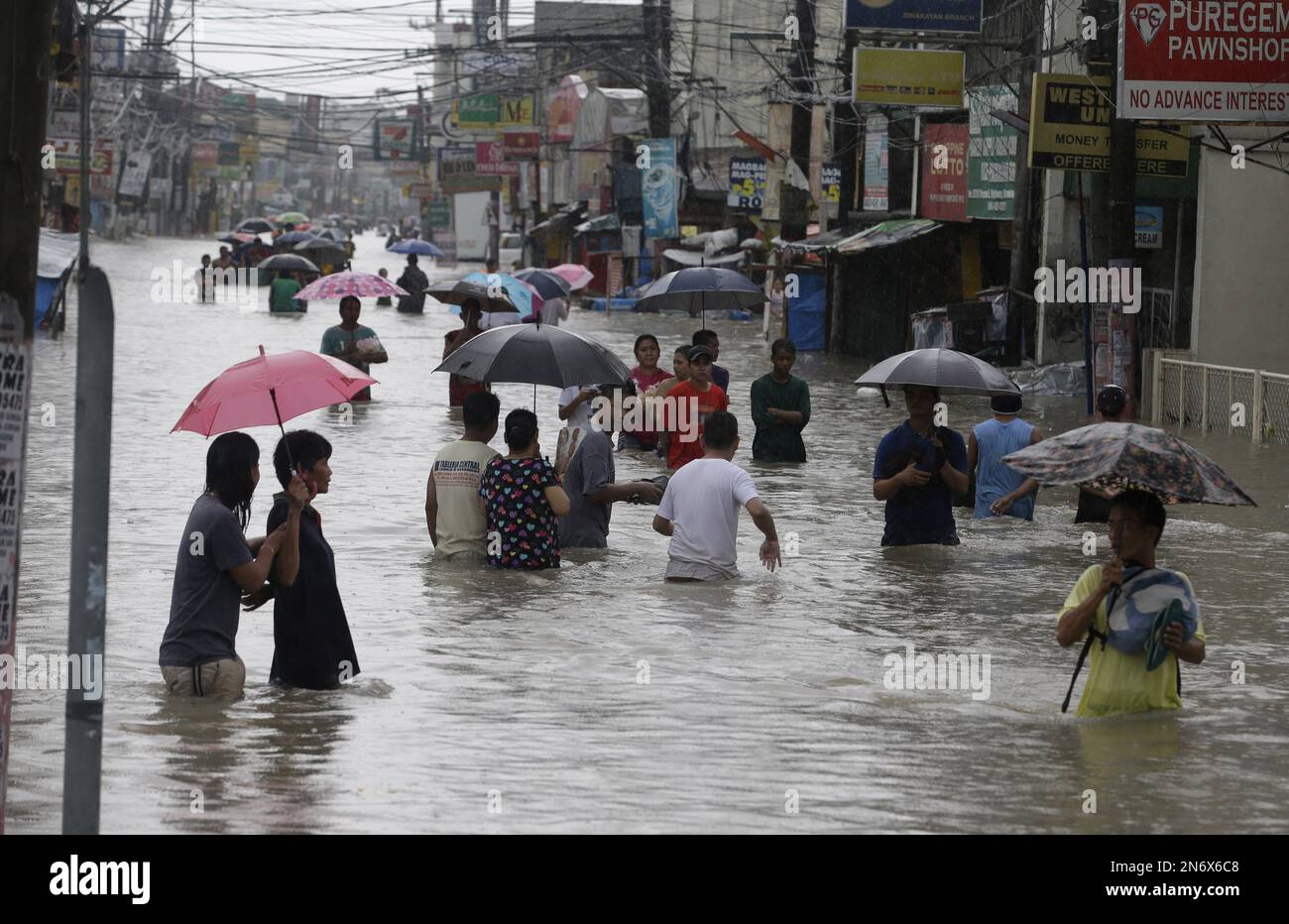 Residents wade through a flooded street in Binakayan township, Cavite ...