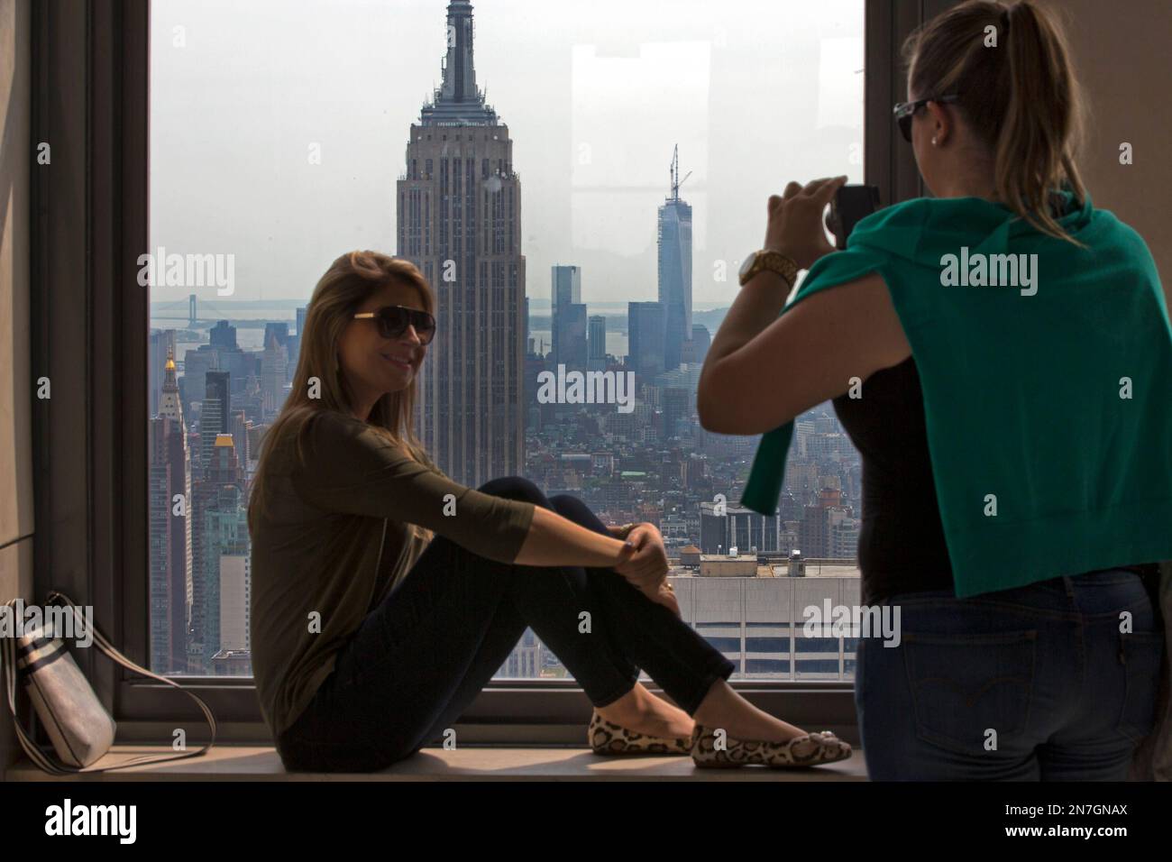 A woman has her picture taken with the 1,454-foot Empire State Building ...