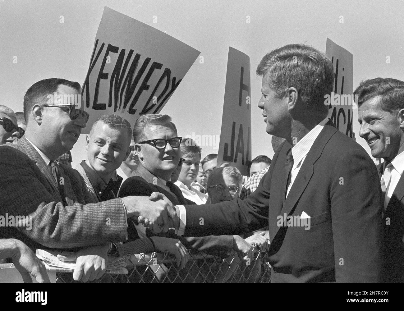 President John F. Kennedy greets a placard-waving crowd as he arrives ...