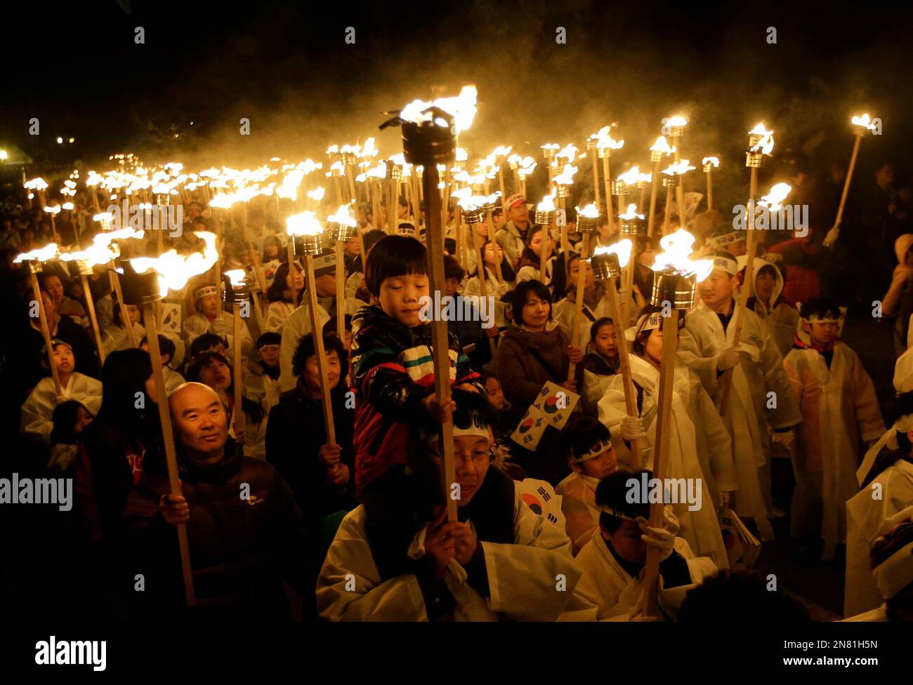 South Koreans, wearing traditional Korean costumes, carry torches while ...